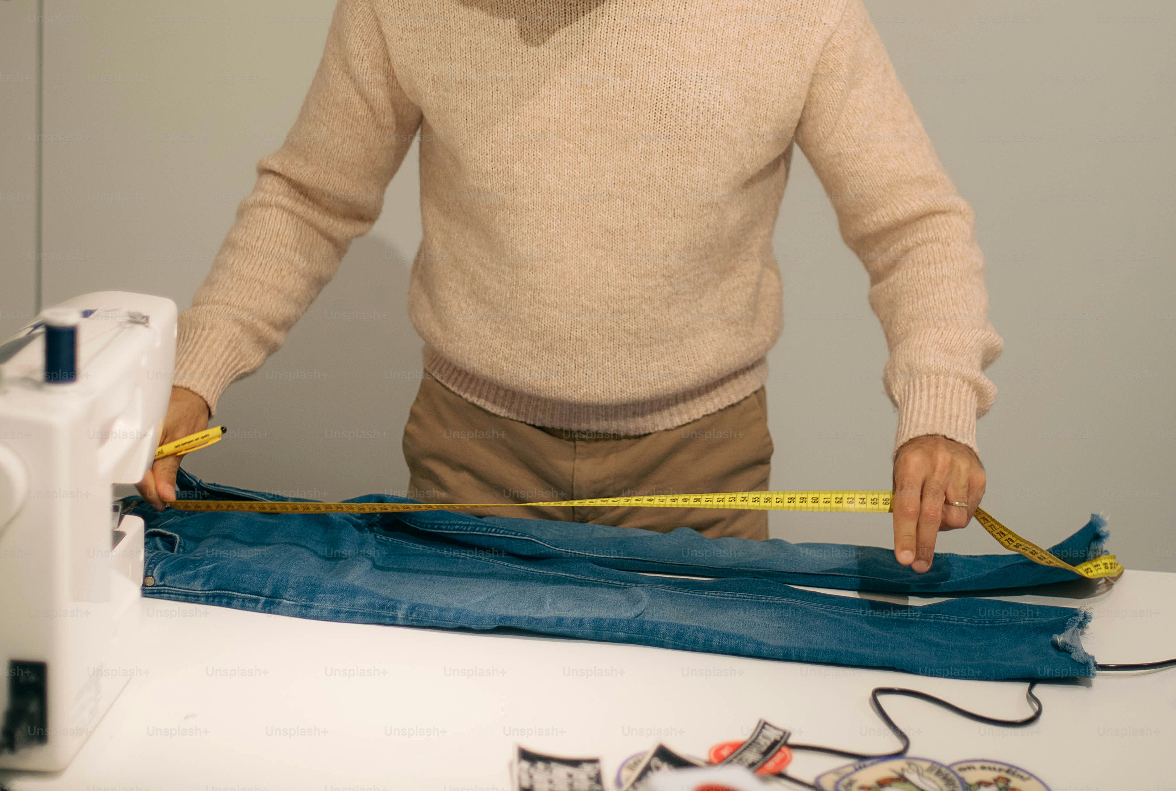 Person measuring blue jeans with a tape measure. photo – Fabric Image ...