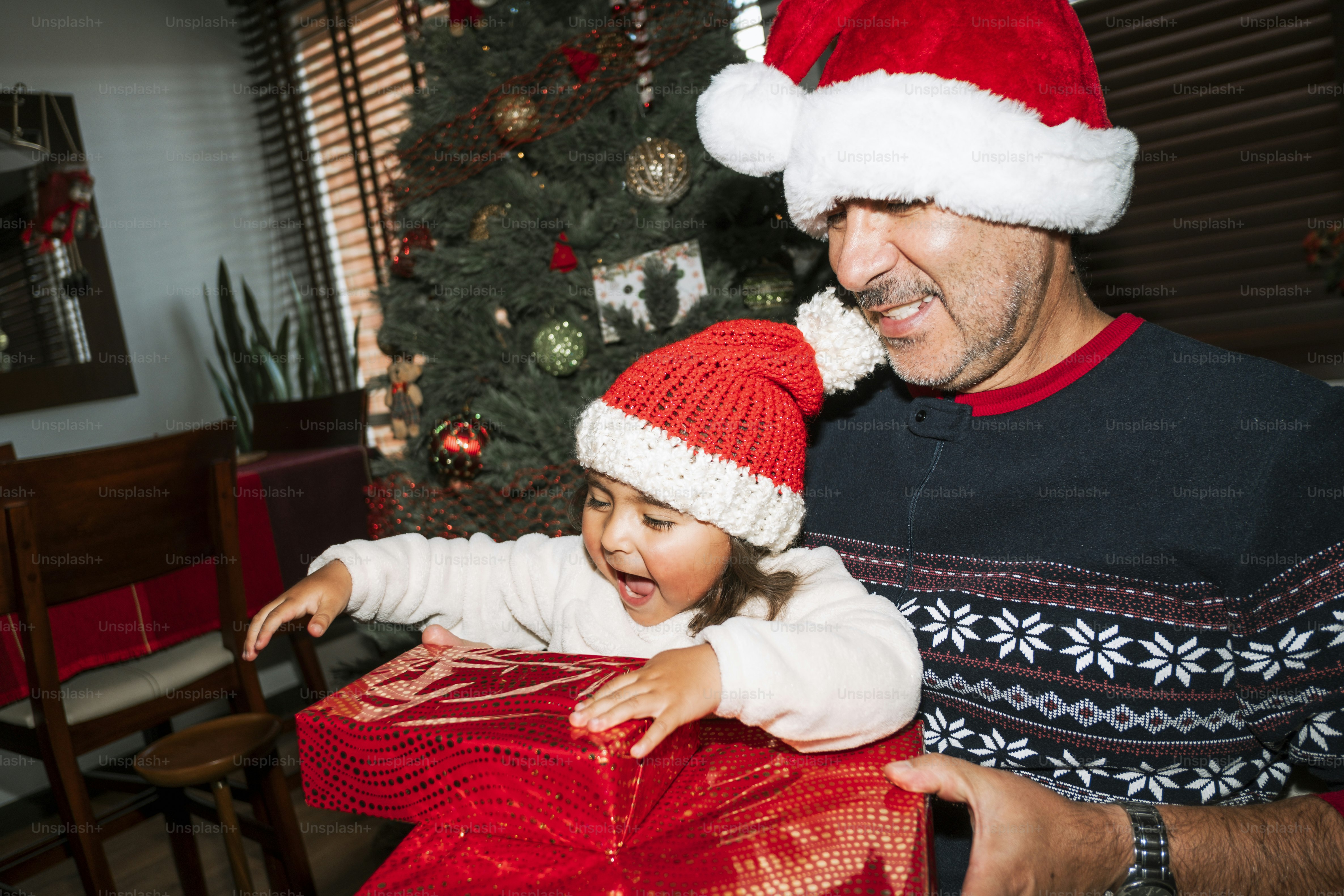 Father and daughter opening a christmas gift. photo – Christmas tree ...