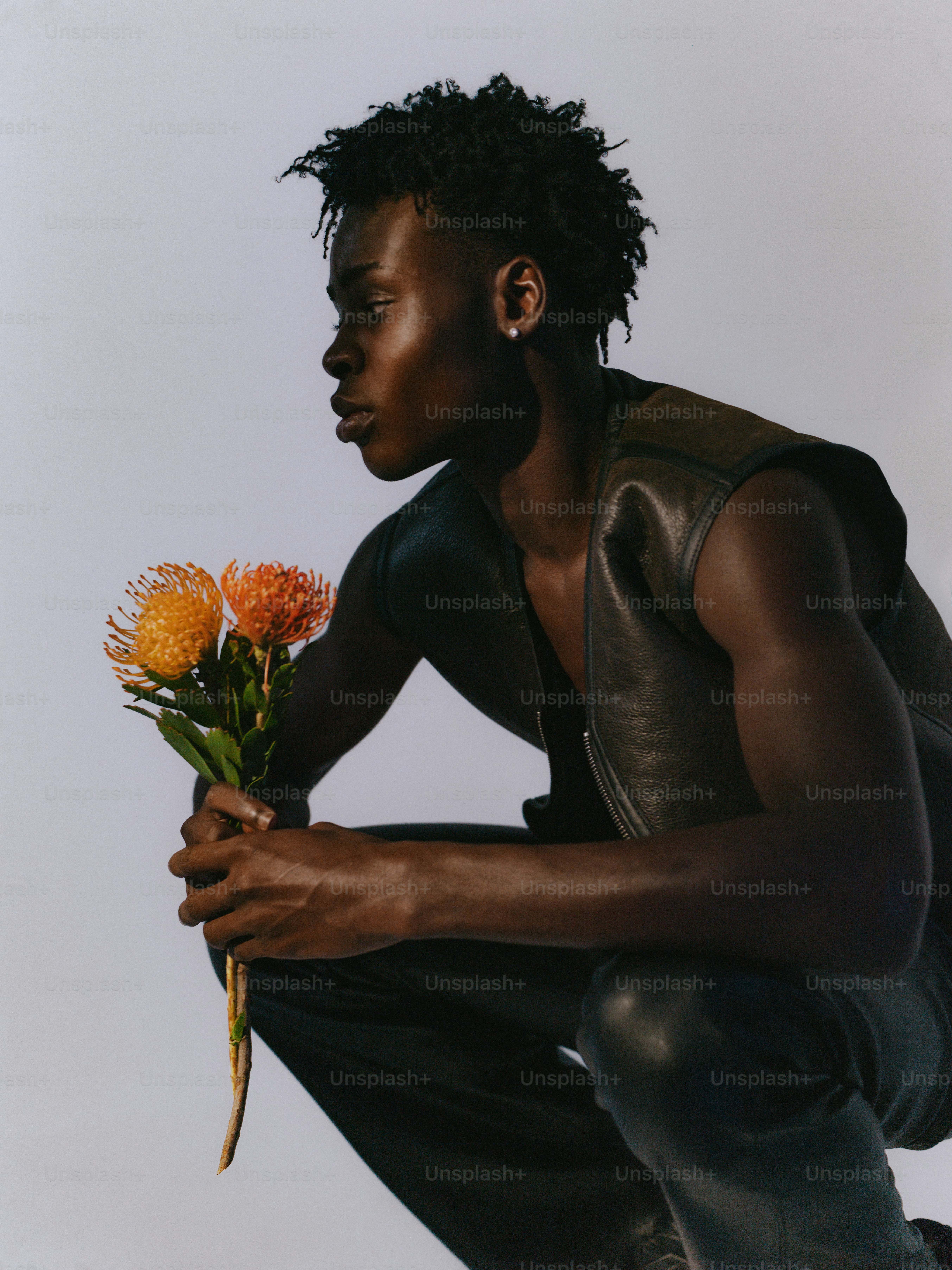 A man in leather pants holds an orange flower. photo – Portrait Image ...
