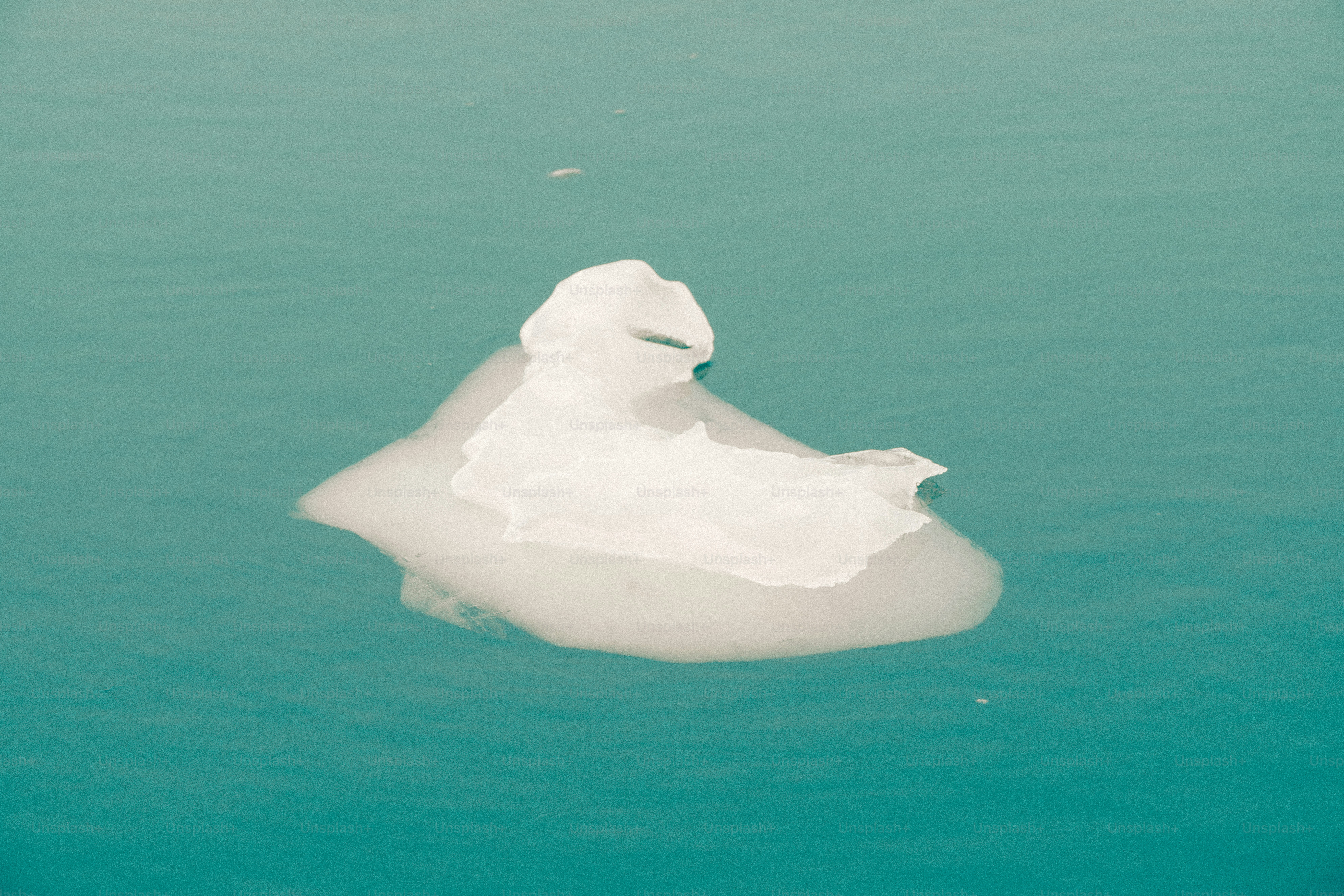 A small iceberg floats in turquoise water. photo – Blue Image on Unsplash