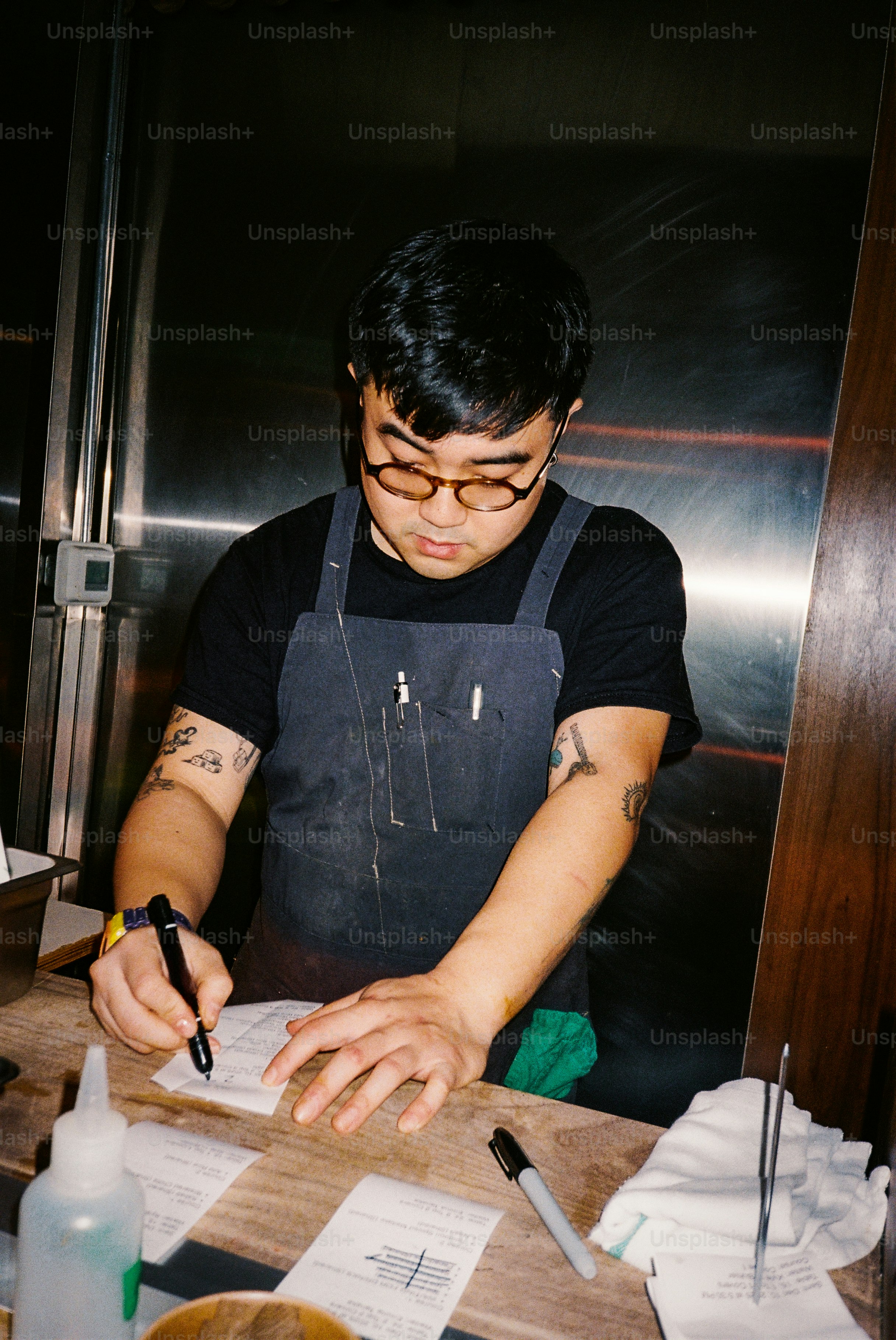 A chef writing on paper in a kitchen. photo – Restaurant Image on Unsplash