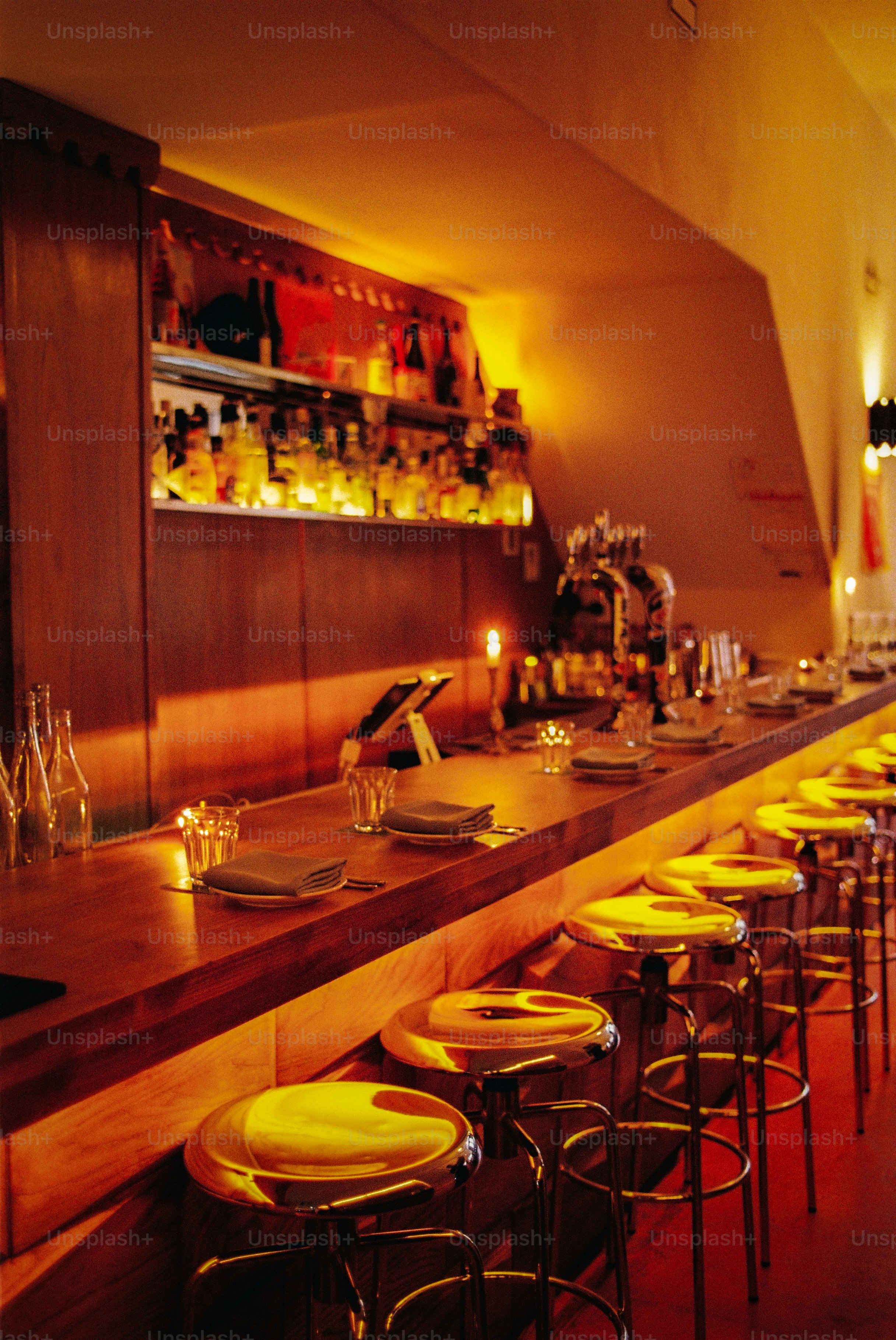 A dimly lit bar with rows of stools and bottles. photo – Restaurant ...
