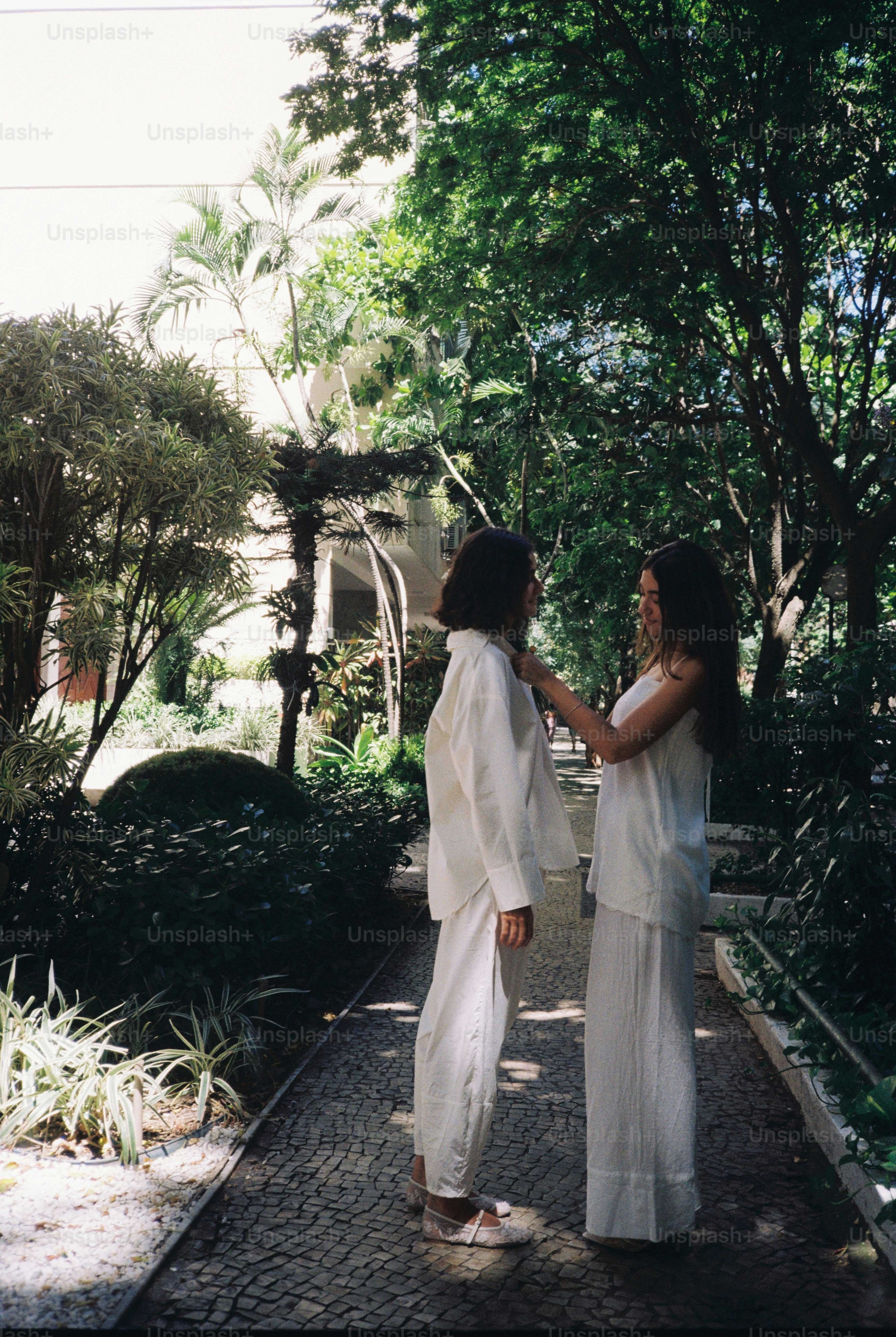Two women in white outfits standing outside a building. photo – City ...