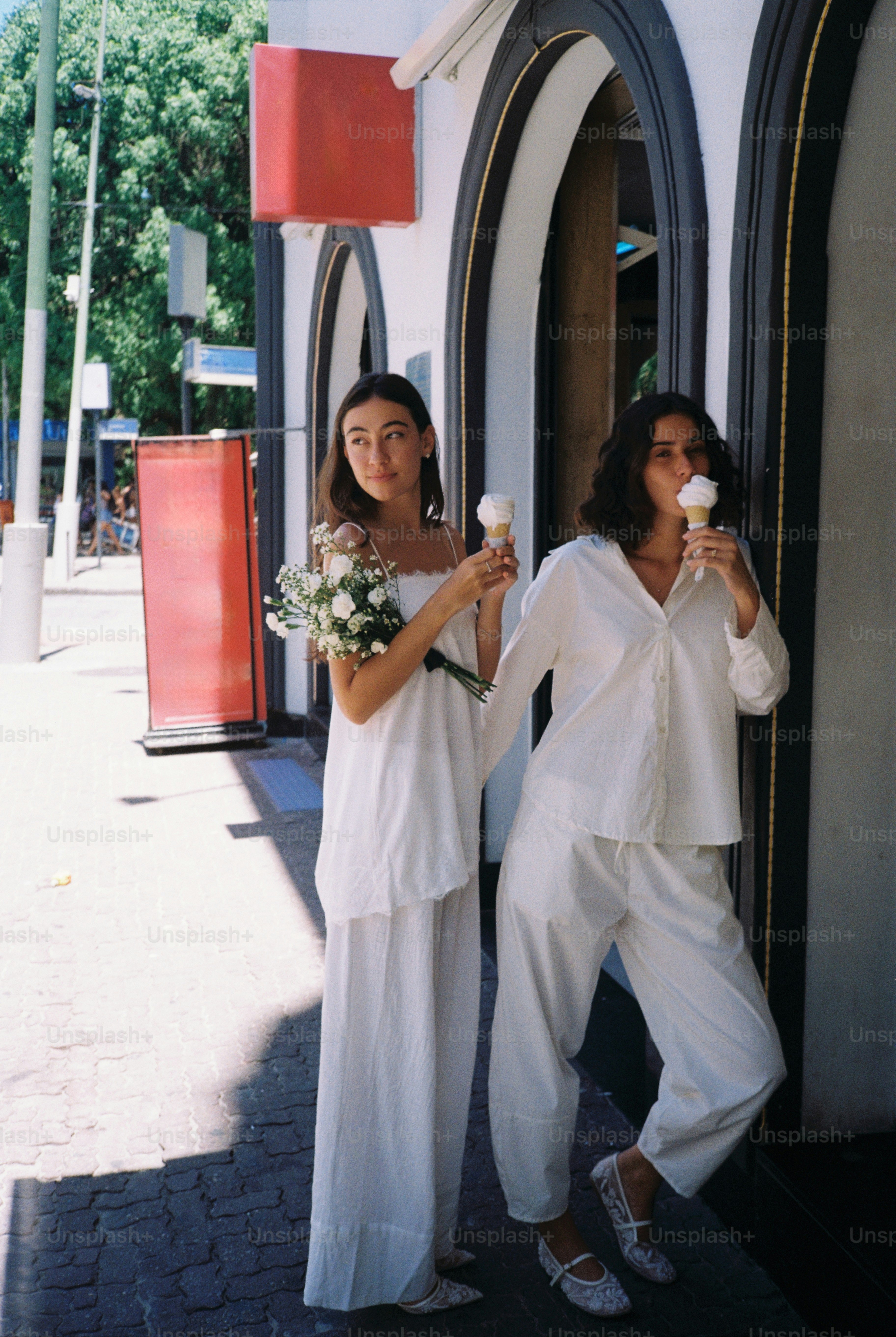 Two women in white outfits standing outside a building. photo – City ...