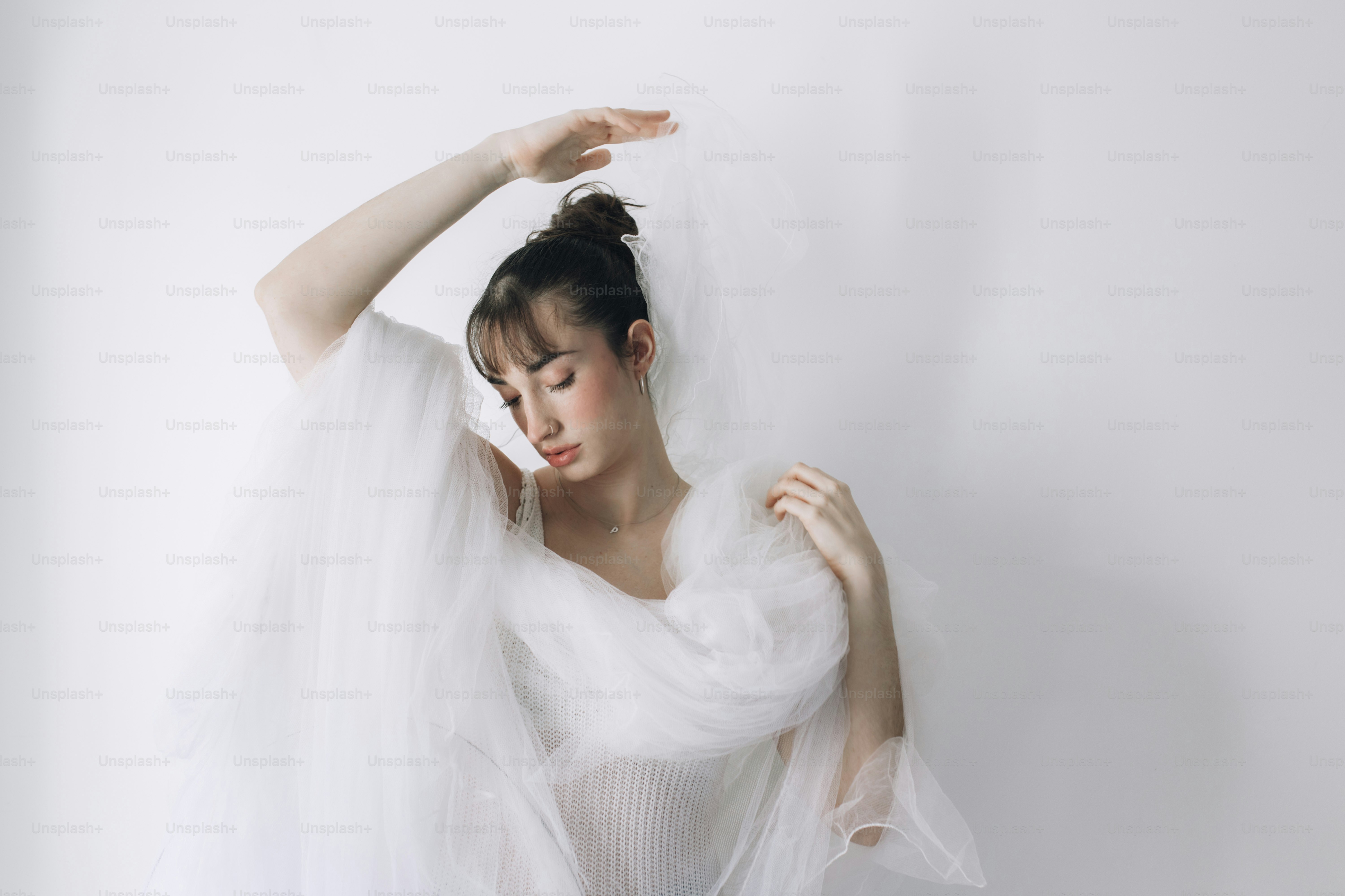 Young woman in flowing white fabric against white background photo ...