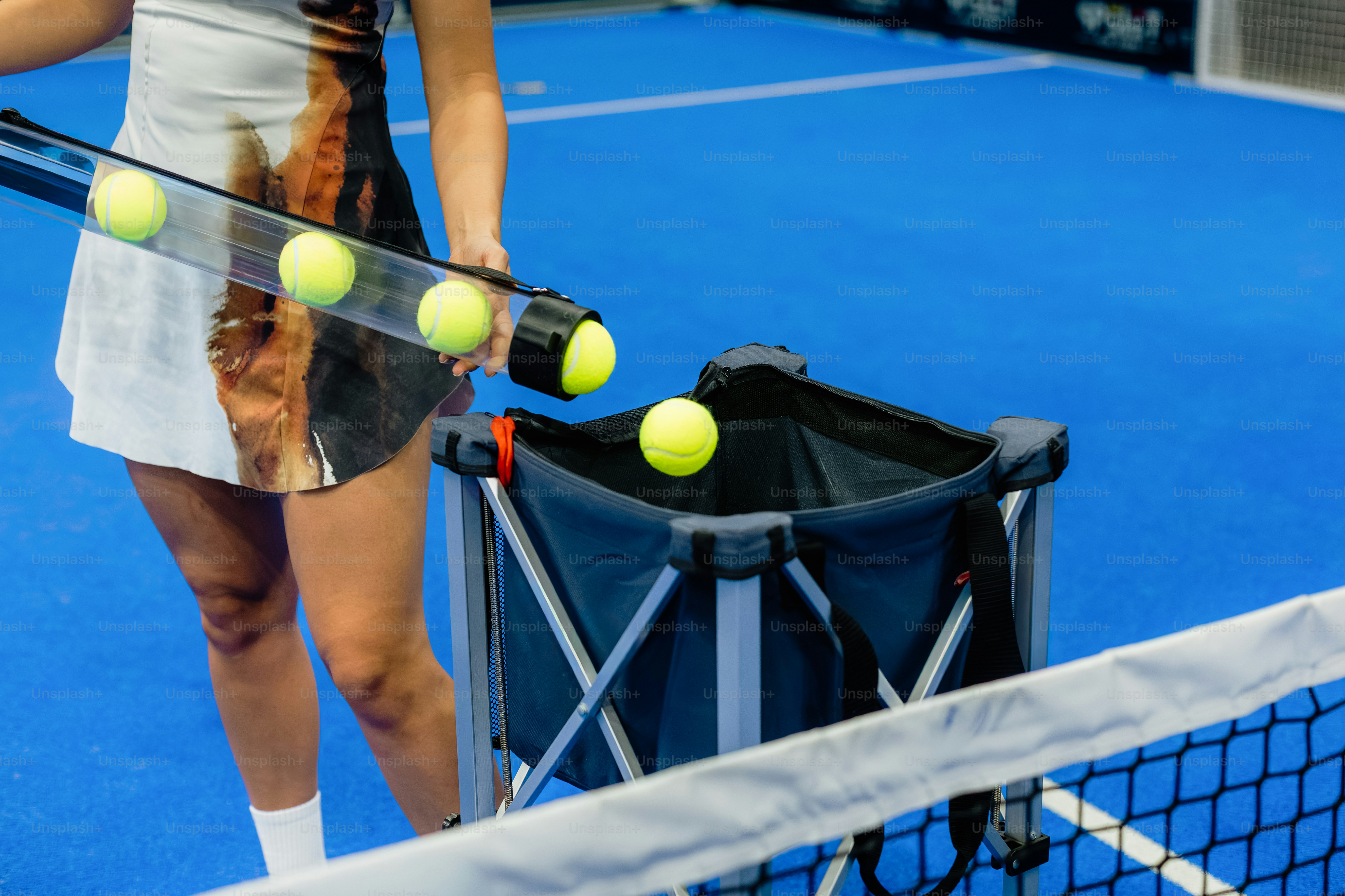 Femme remplissant des balles de tennis dans un panier sur le court ...