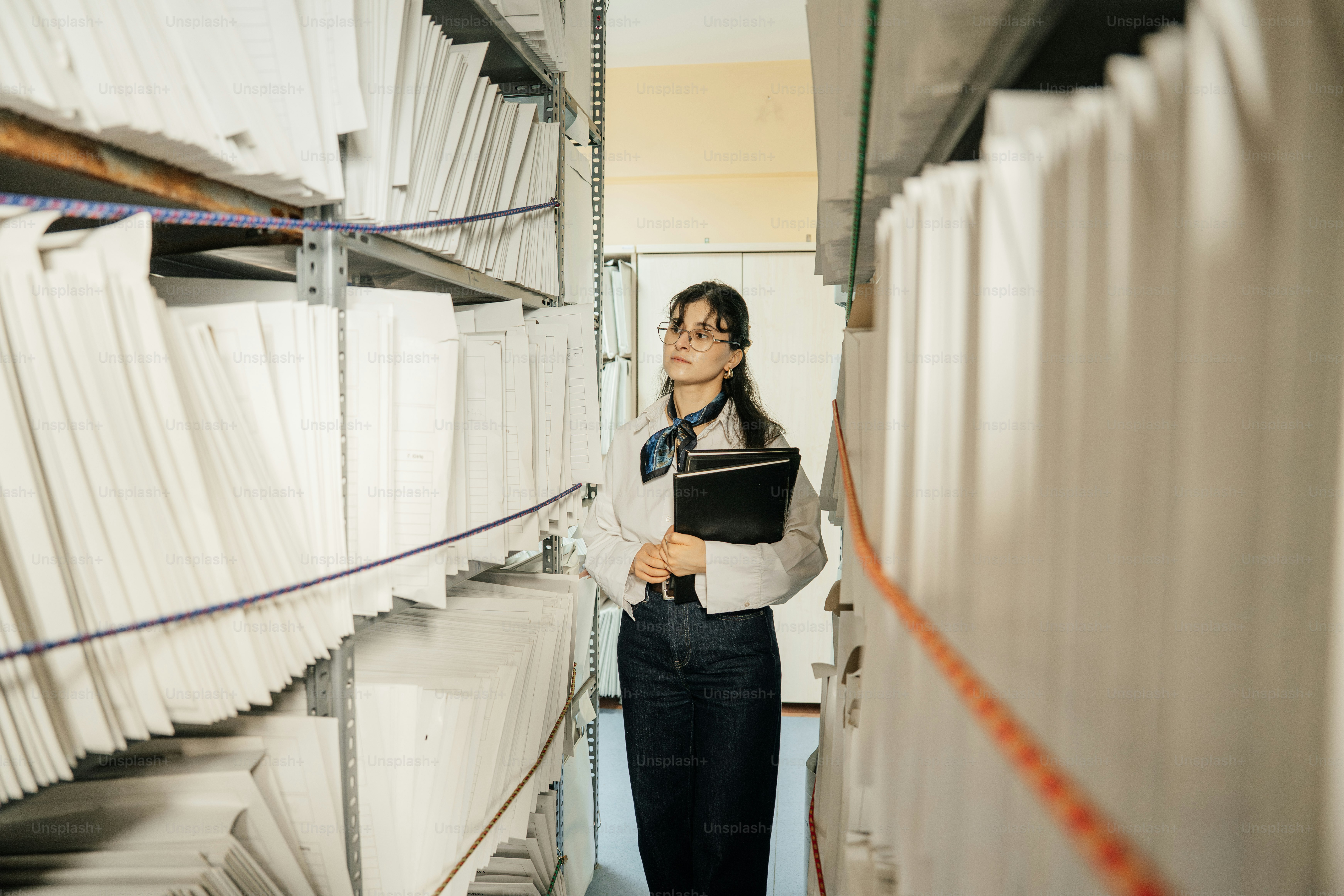 Woman organizing files in a large archive photo – Documents Image on ...