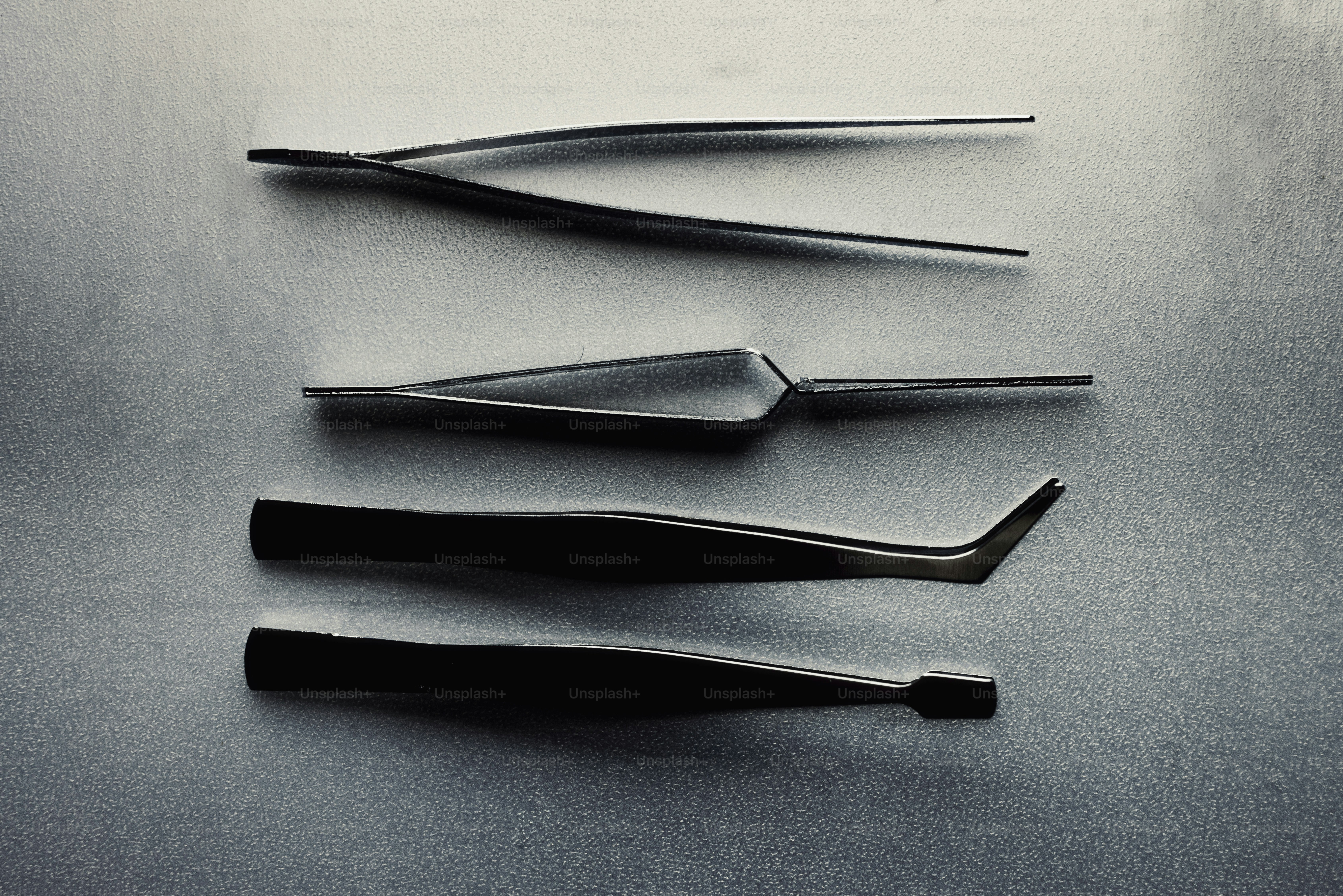 Four different types of tweezers on a surface photo – Texture Image on ...