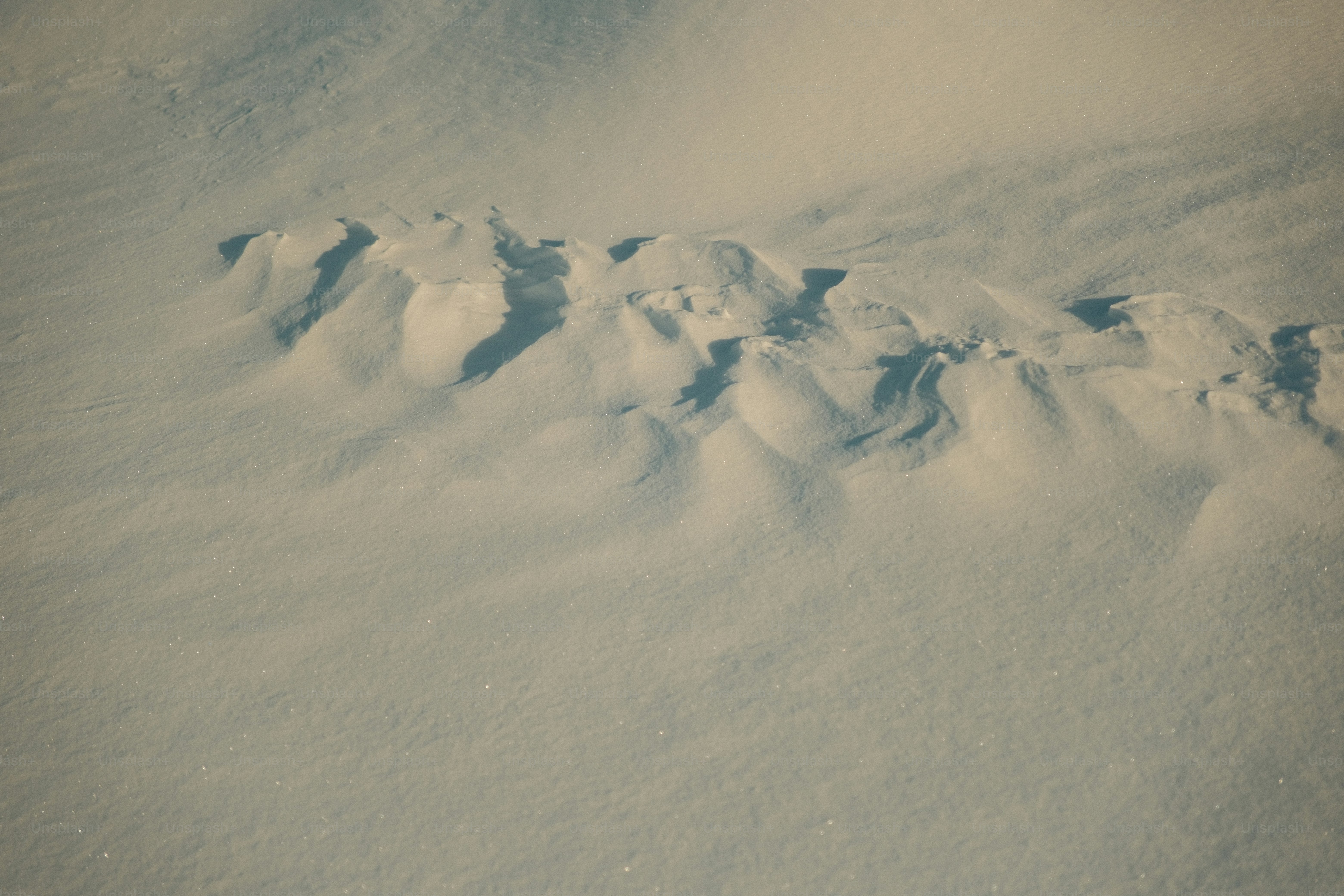 Drifted snow forms textured patterns on a pale background. photo ...
