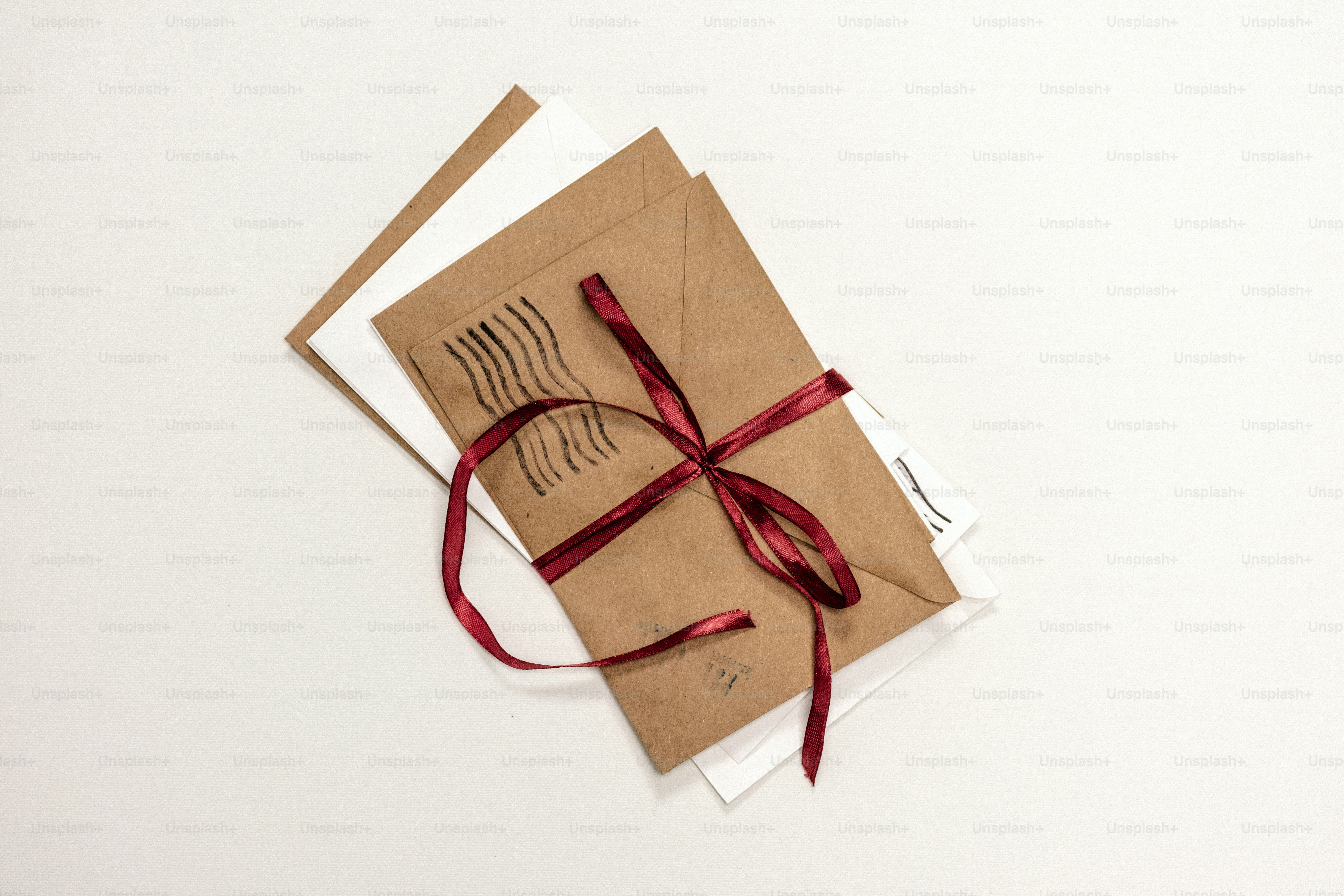 Brown envelope tied with a red ribbon on white background photo – Paper ...