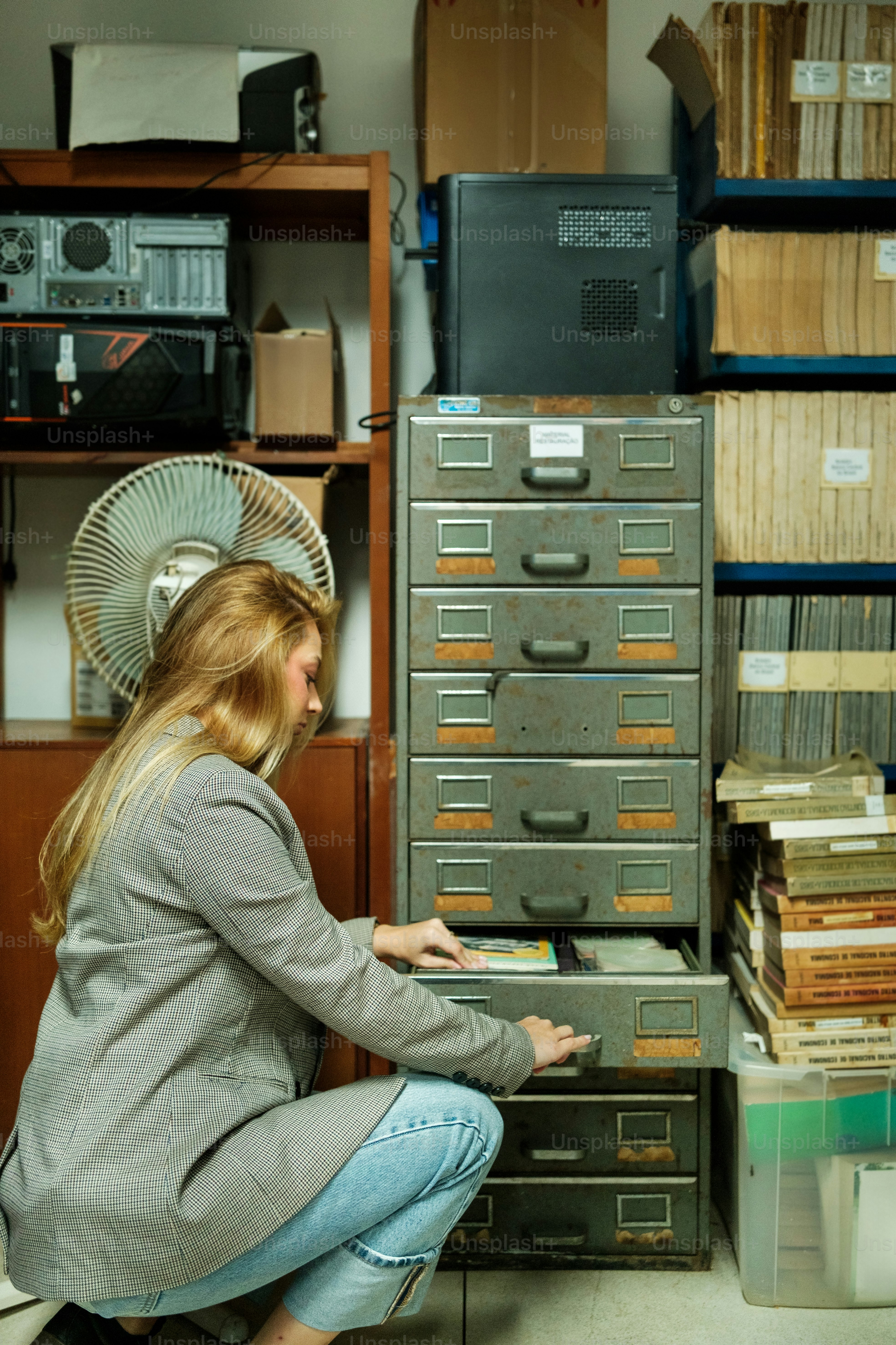 Woman searching through old filing cabinet drawers. photo – Documents ...