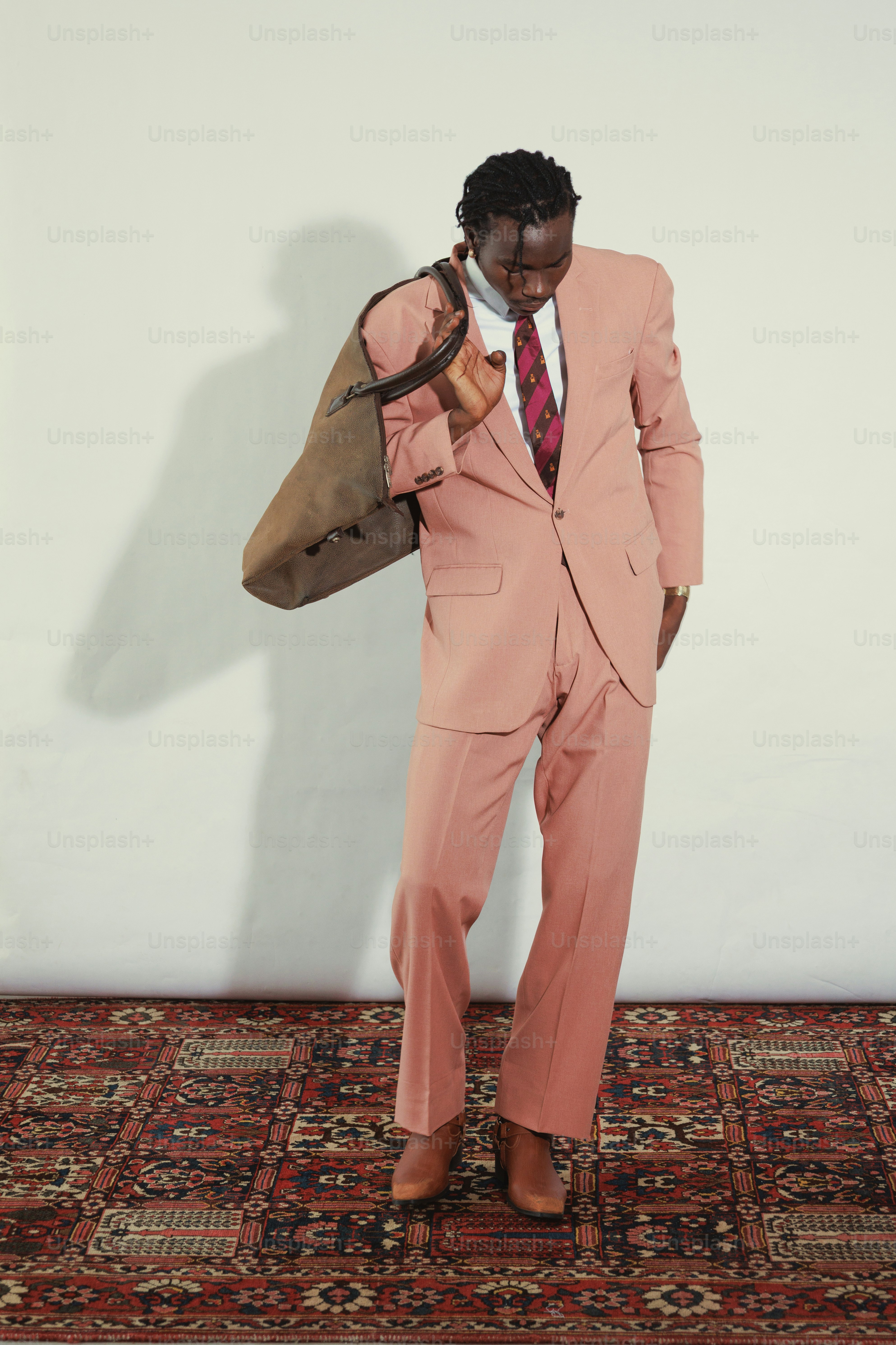 Man in pink suit carrying a bag over shoulder. photo – Mens fashion ...