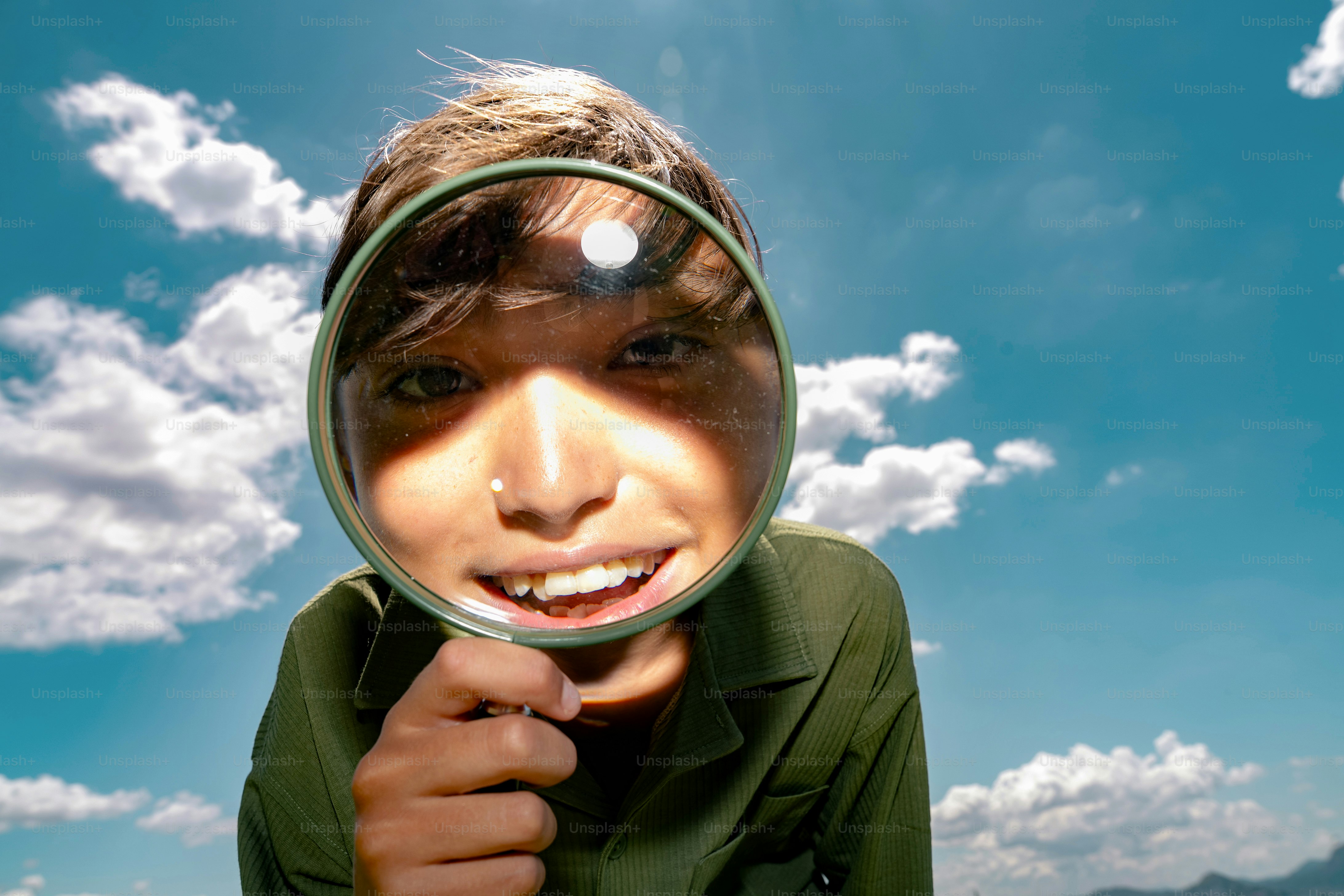A child looks through a magnifying glass at the camera. photo ...