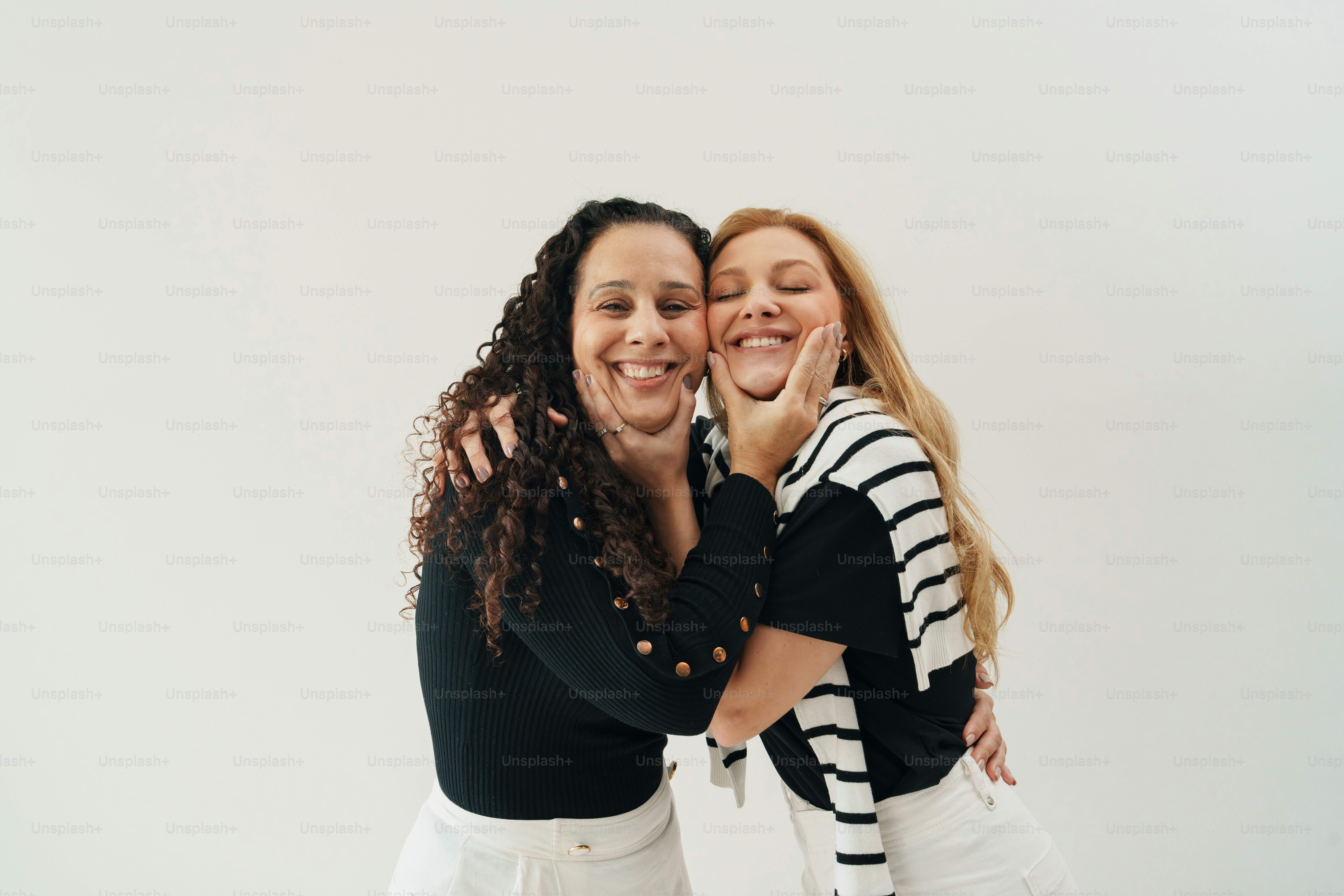 Two smiling women hugging against white background photo – Love Image ...