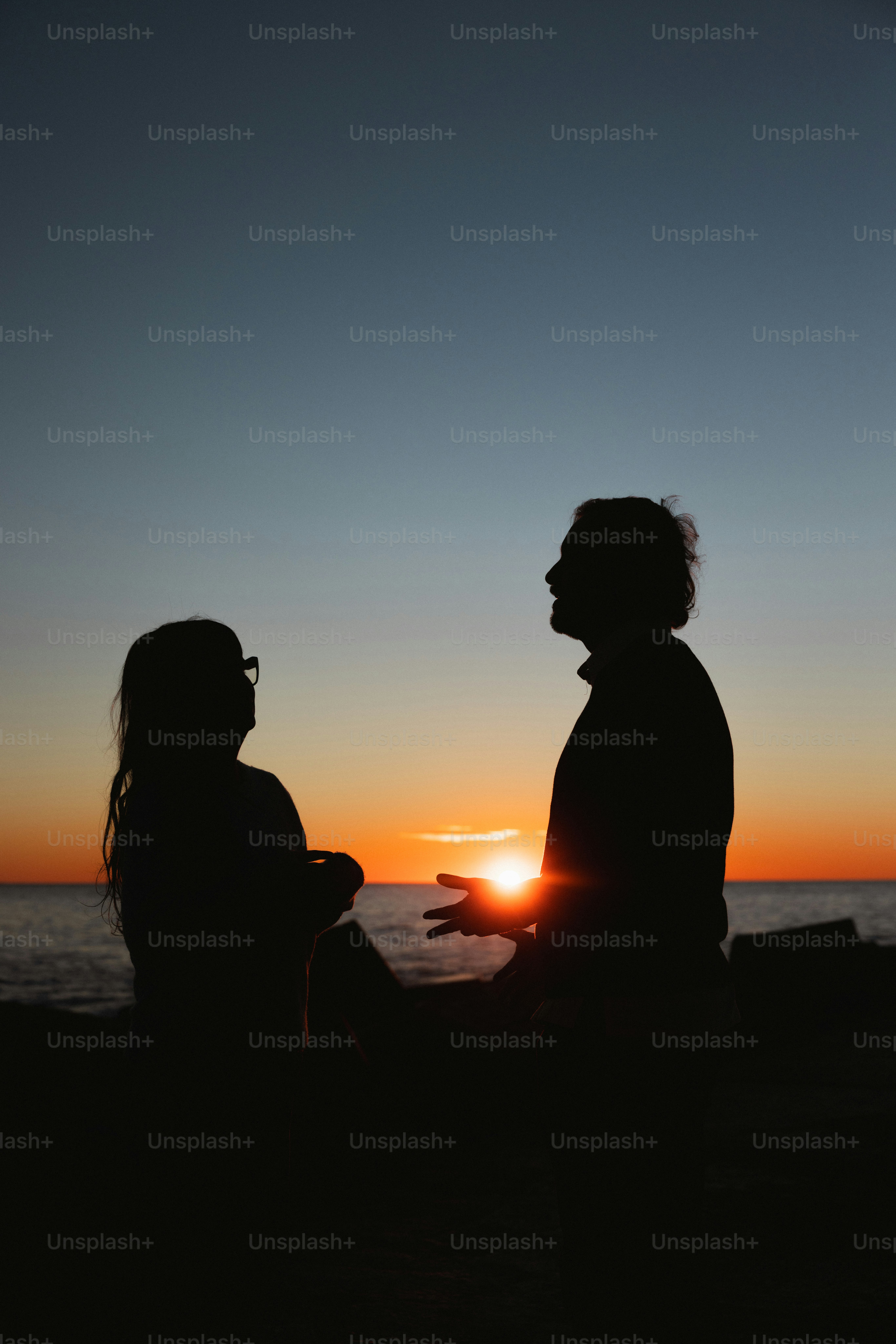 Silhouettes of two people talking at sunset by the ocean photo – Beach ...