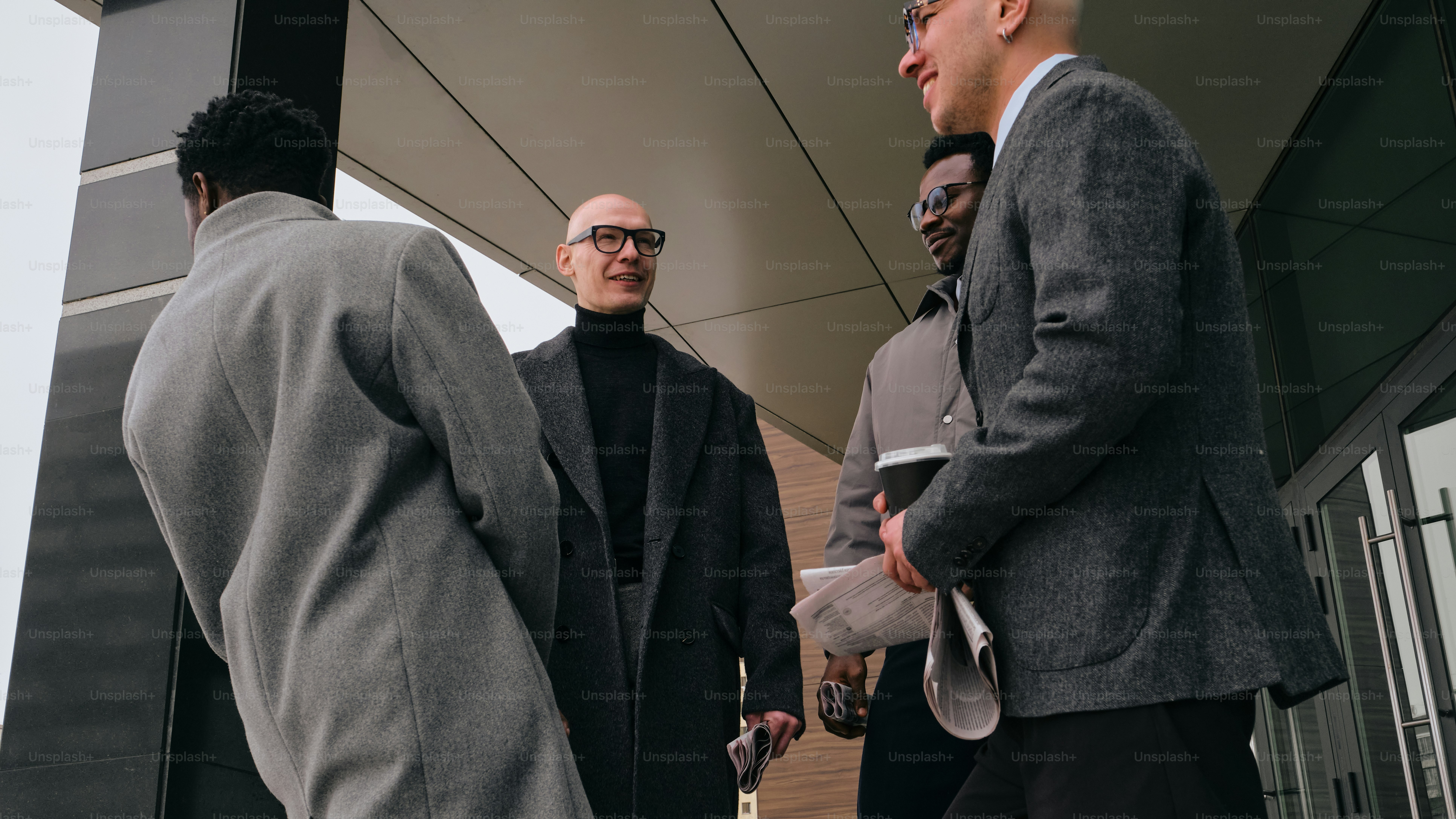 Four men in suits talking outside a modern building. photo – News Image ...
