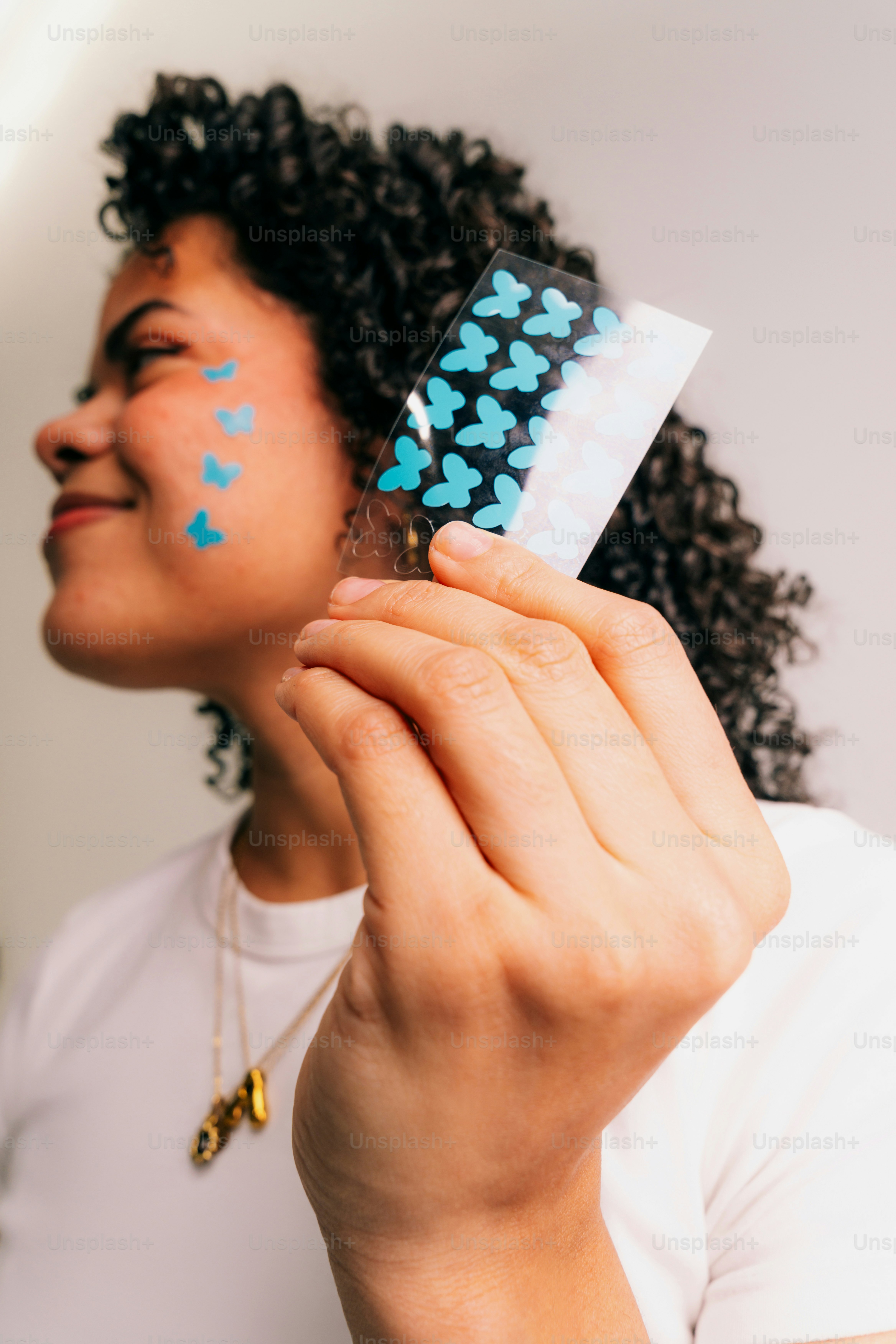 Woman applying blue butterfly face stickers photo – Cosmetic Image on ...