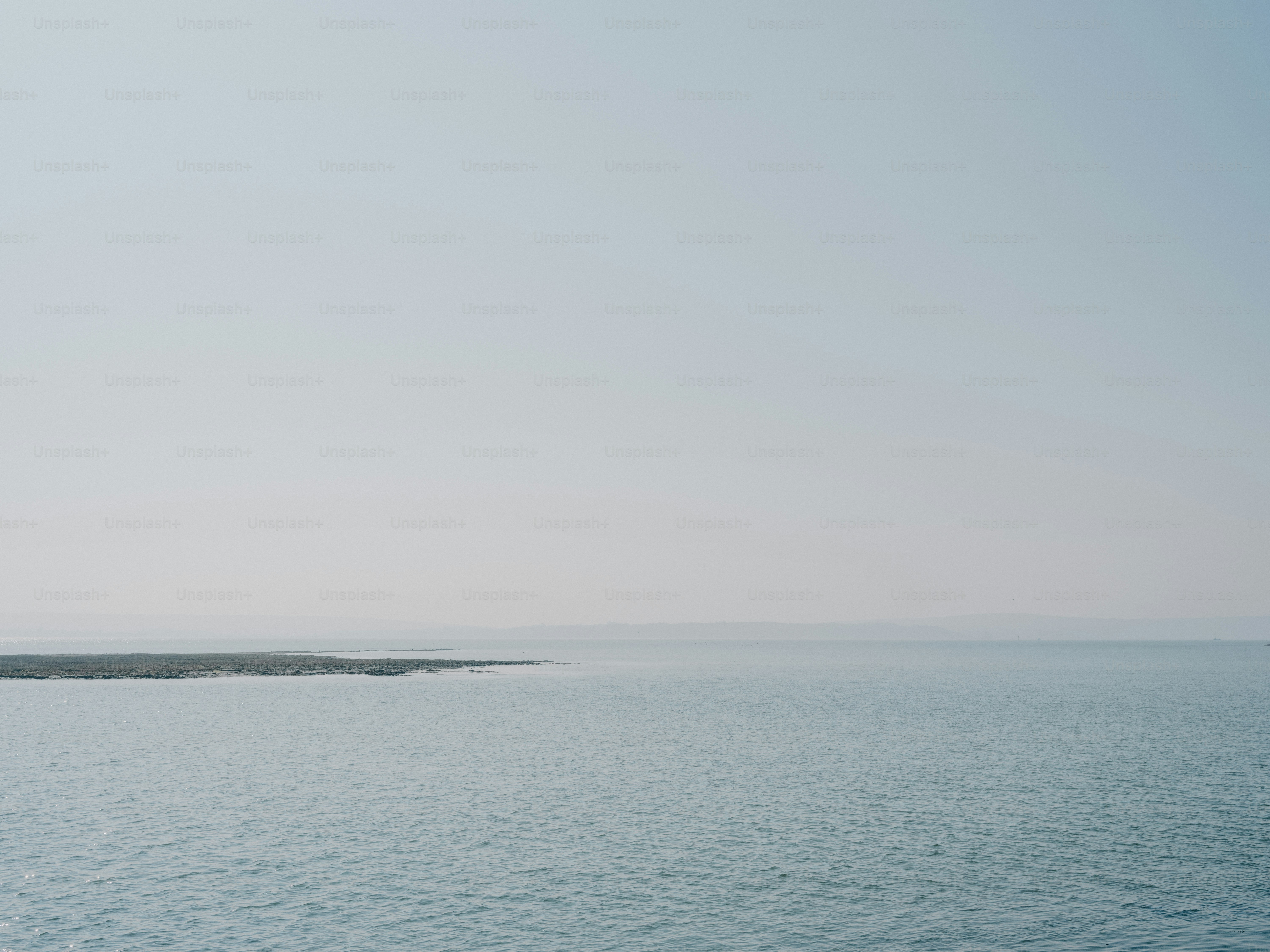 Calm ocean water meets a distant, hazy shoreline. photo – Sea Image on ...