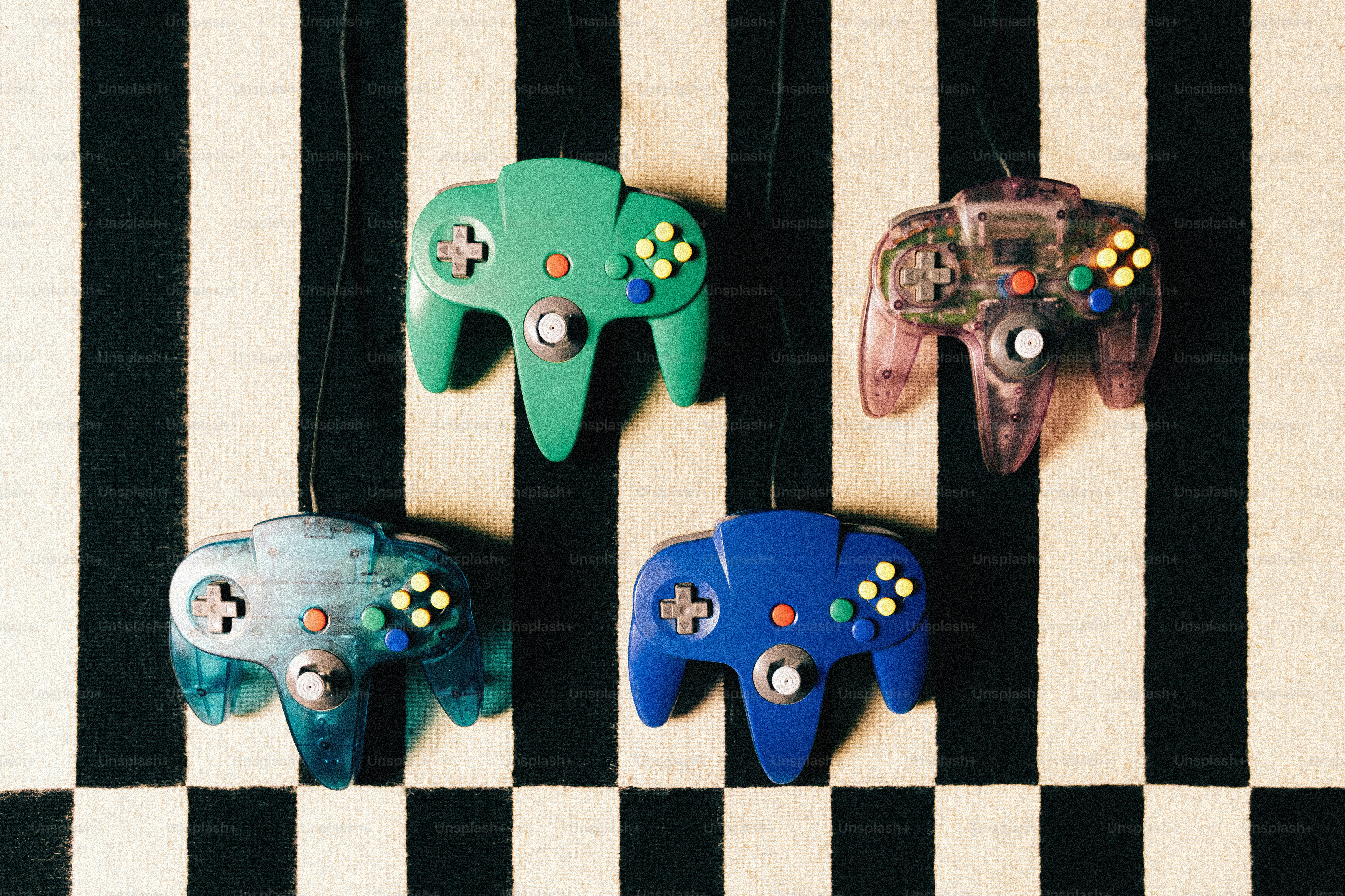 Four video game controllers on a striped surface photo – Technology ...