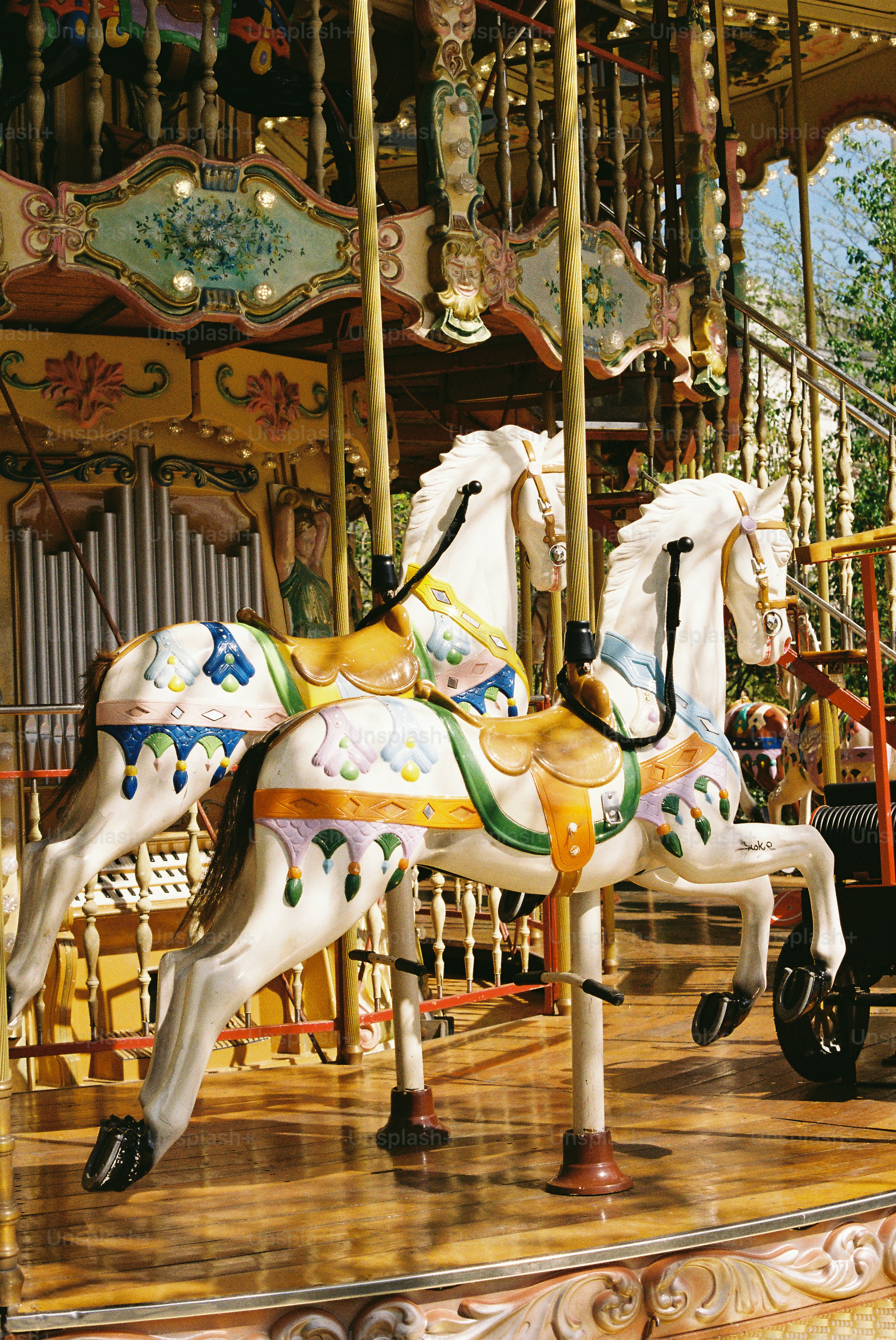 Two white carousel horses with colorful saddles and bridles. photo ...
