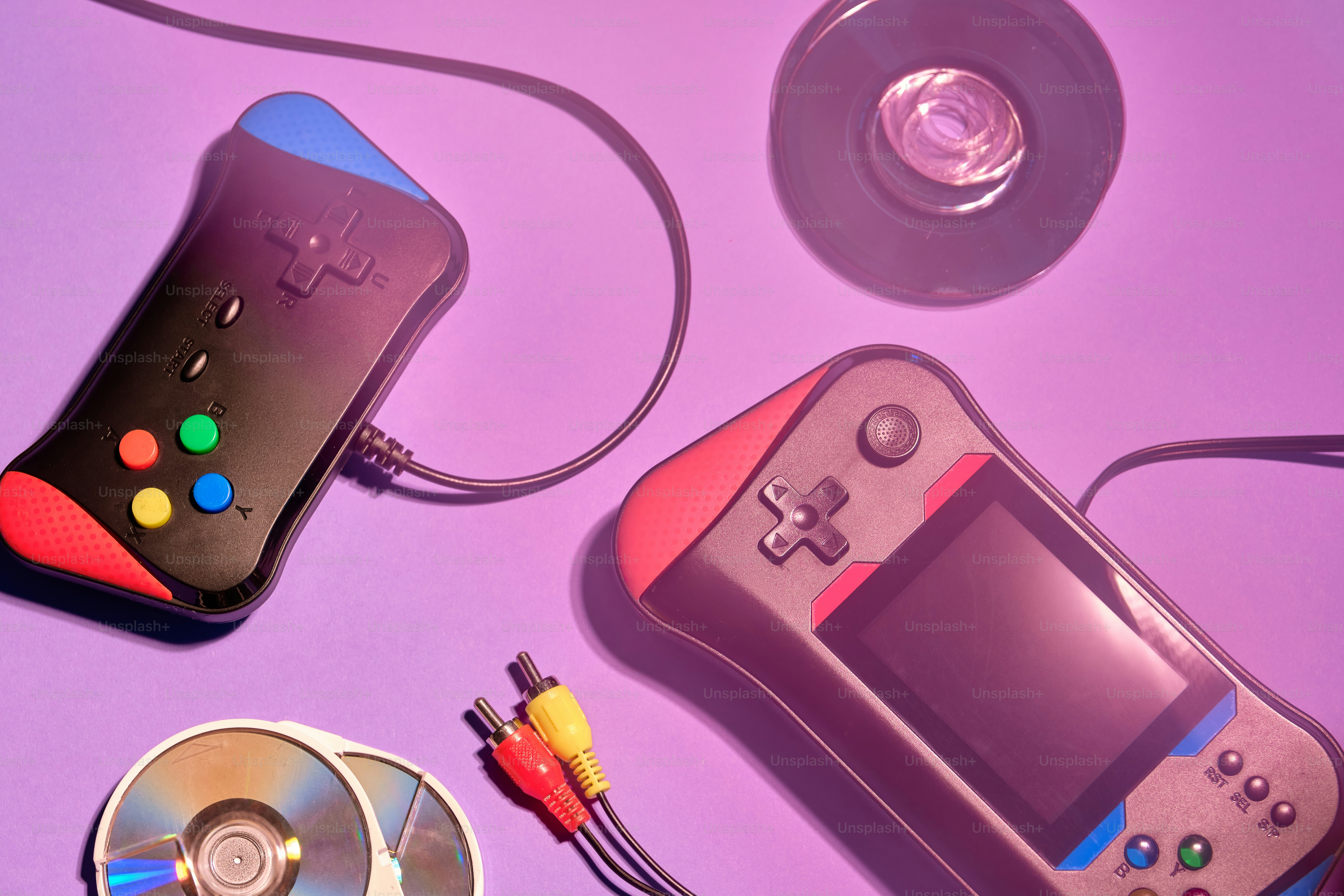 Retro gaming console, controllers, and disc on purple background photo ...