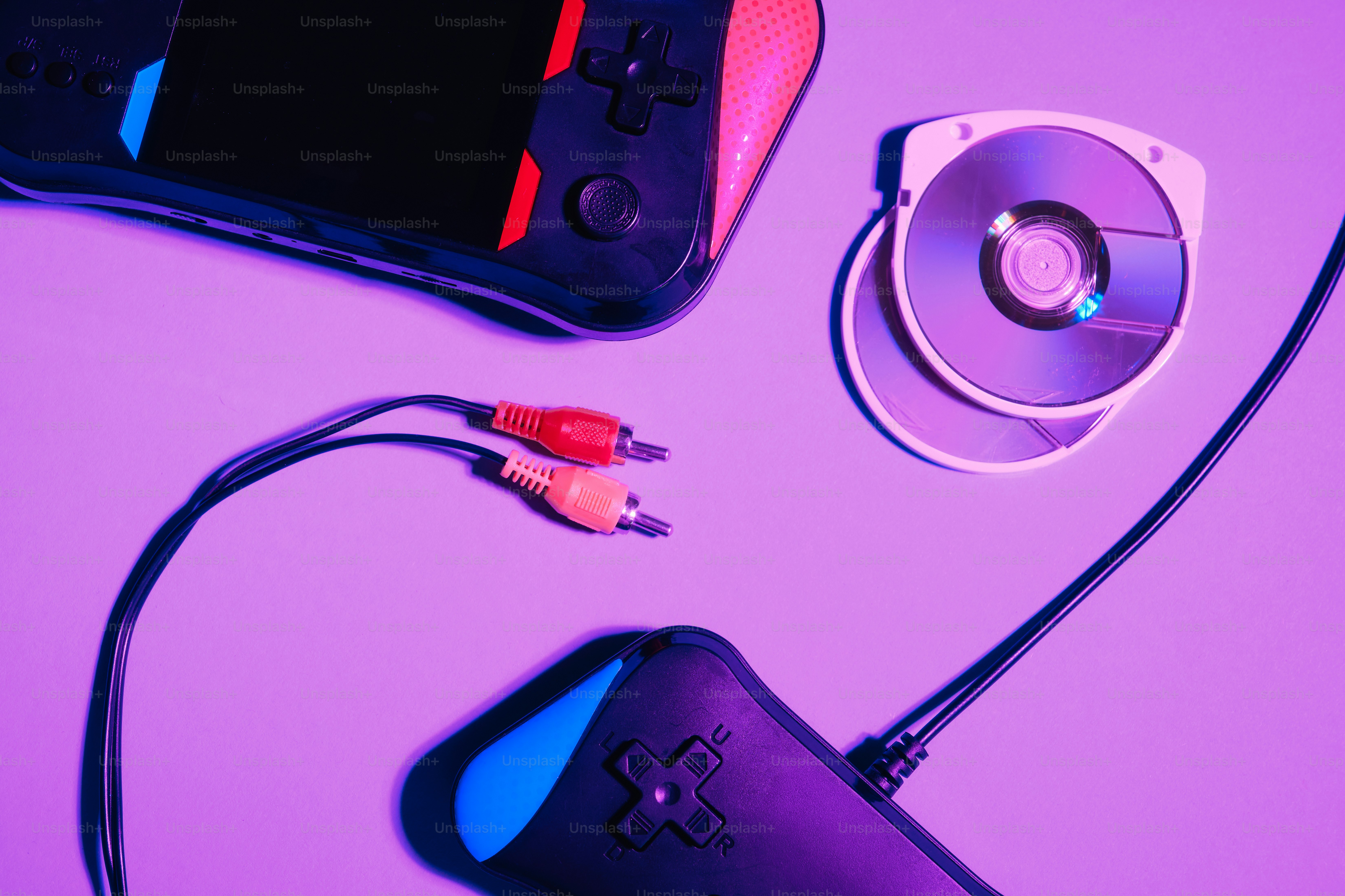 Retro gaming console, controllers, and disc on purple background photo ...