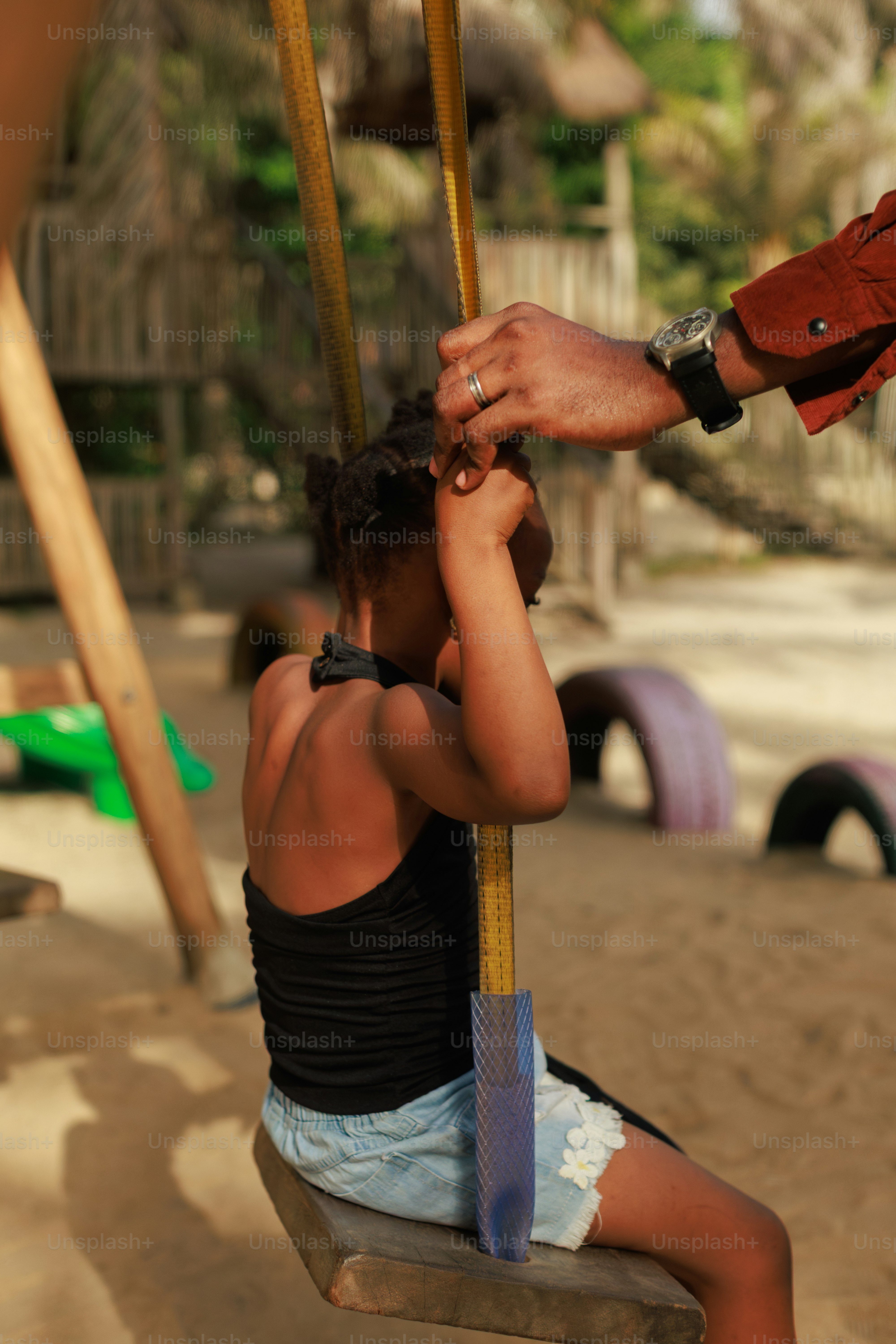 A person braids a child's hair on a swing. photo – Park Image on Unsplash