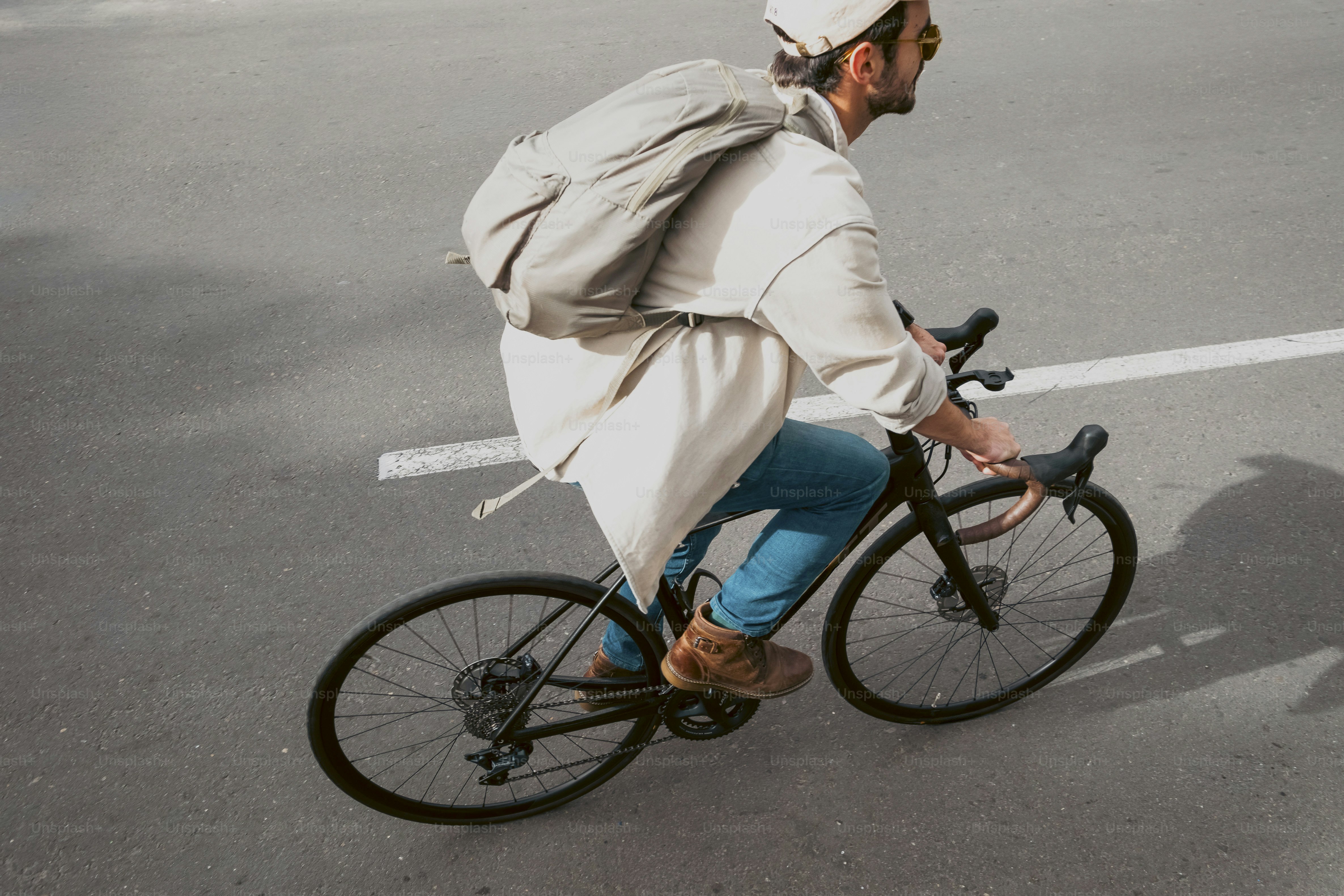Man riding a bicycle with a backpack and helmet. photo – Health Image ...
