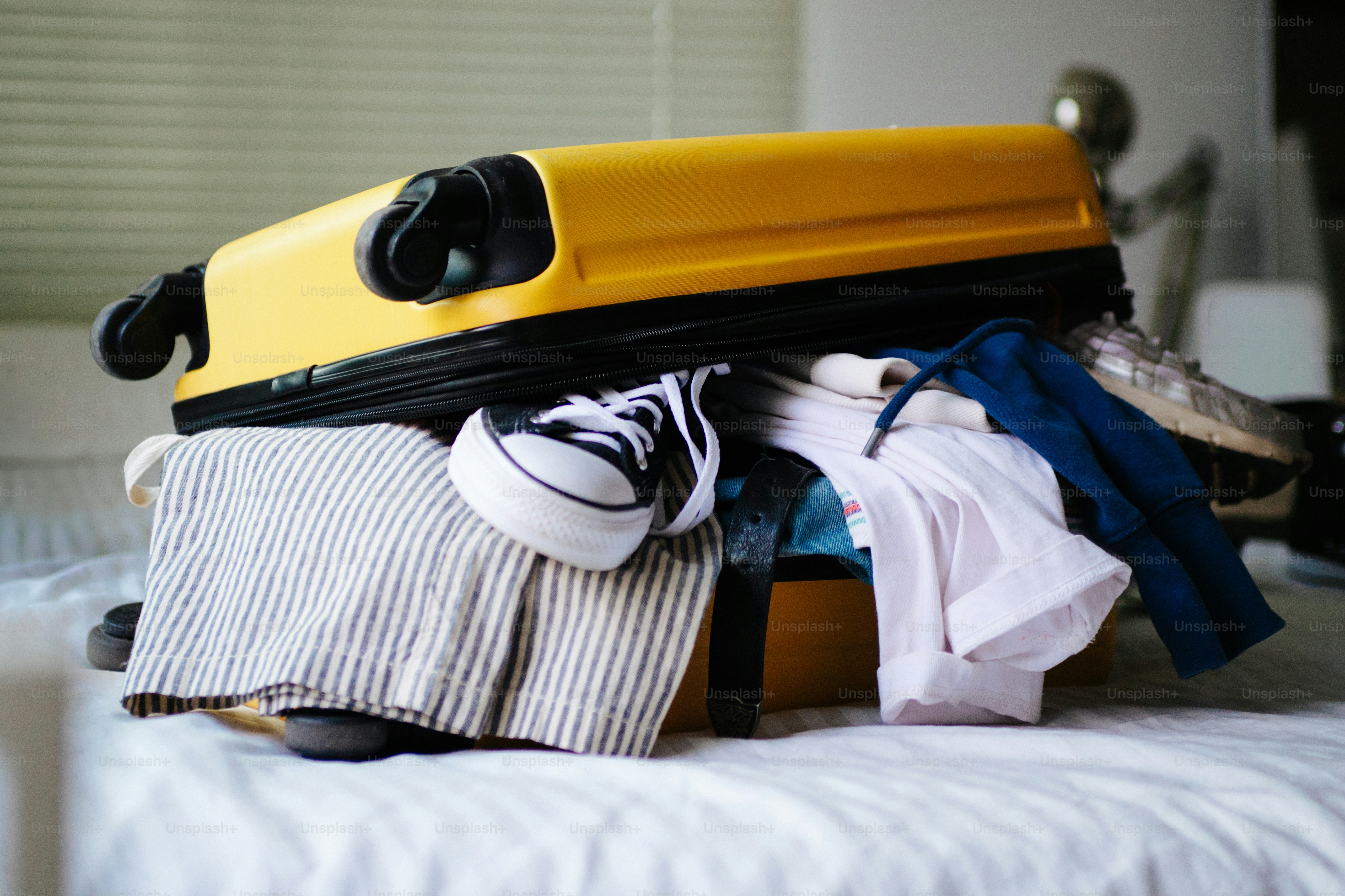 Yellow suitcase overflowing with clothes and shoes on green sofa. photo ...
