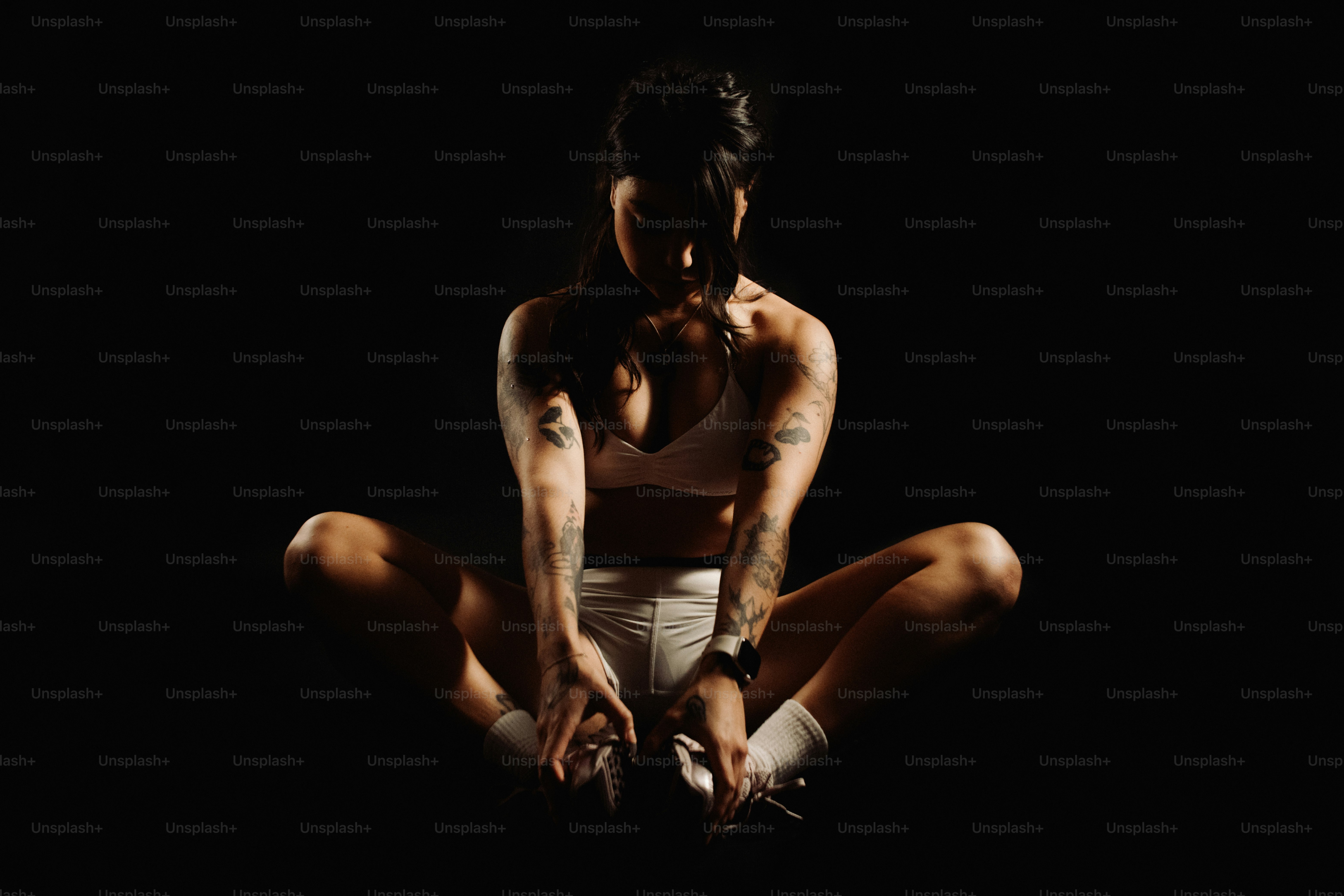 Woman stretching in athletic wear against a dark background. photo ...