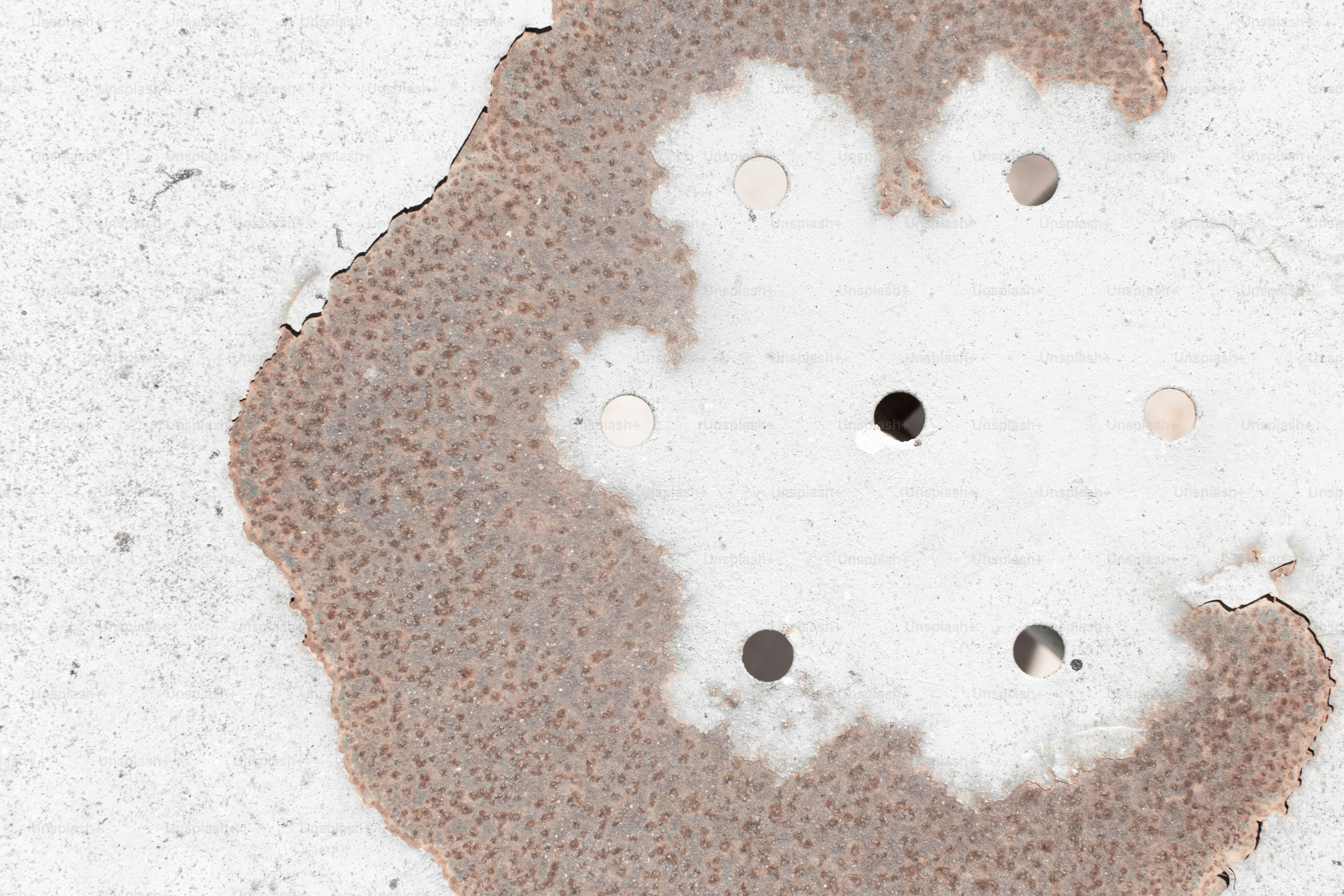 Textured white surface with an irregular brown stain and holes. photo ...