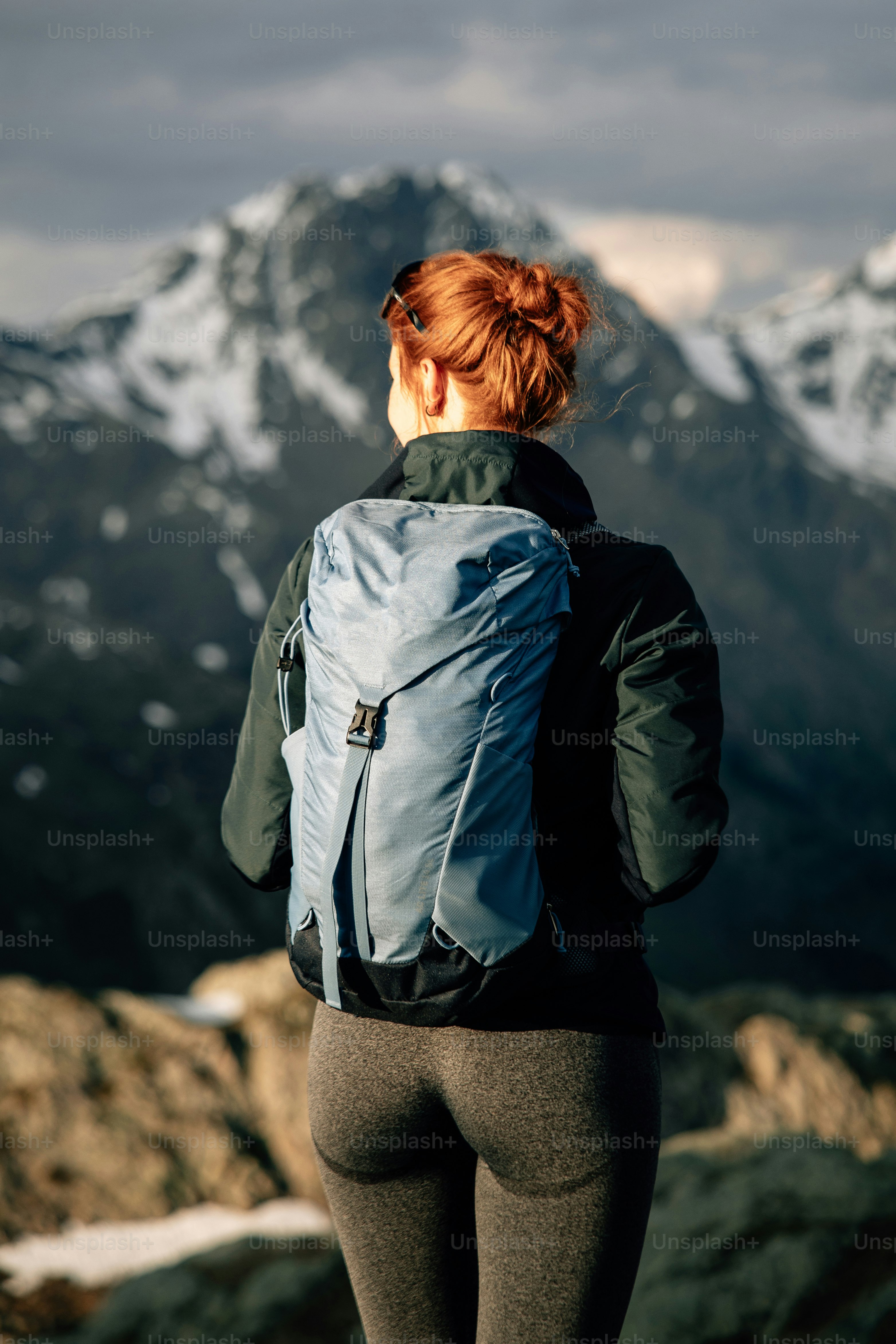 A person with a backpack looking at snowy mountains. photo – Mountains ...