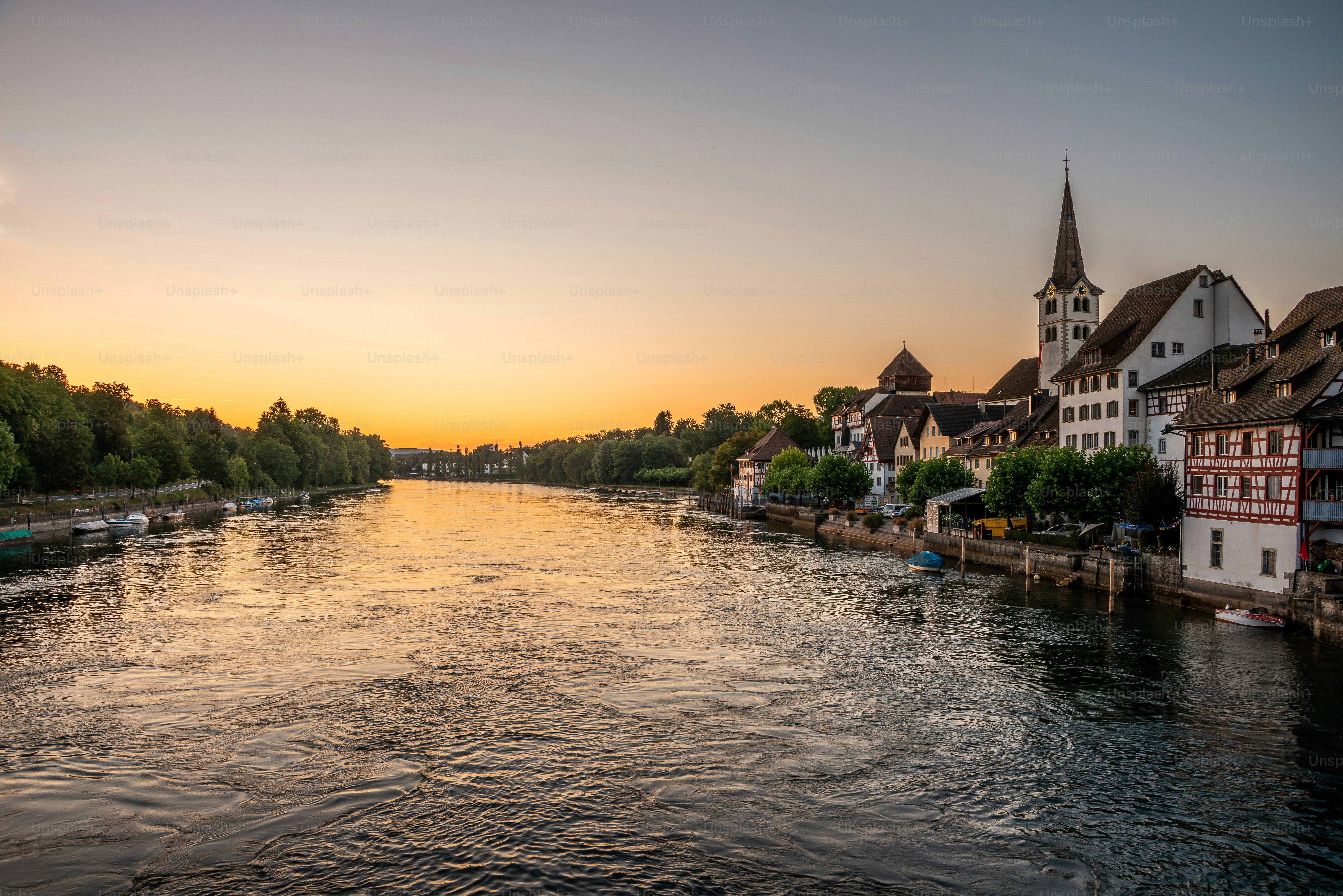 Historic town and wooden bridge reflected in river at sunset. photo ...